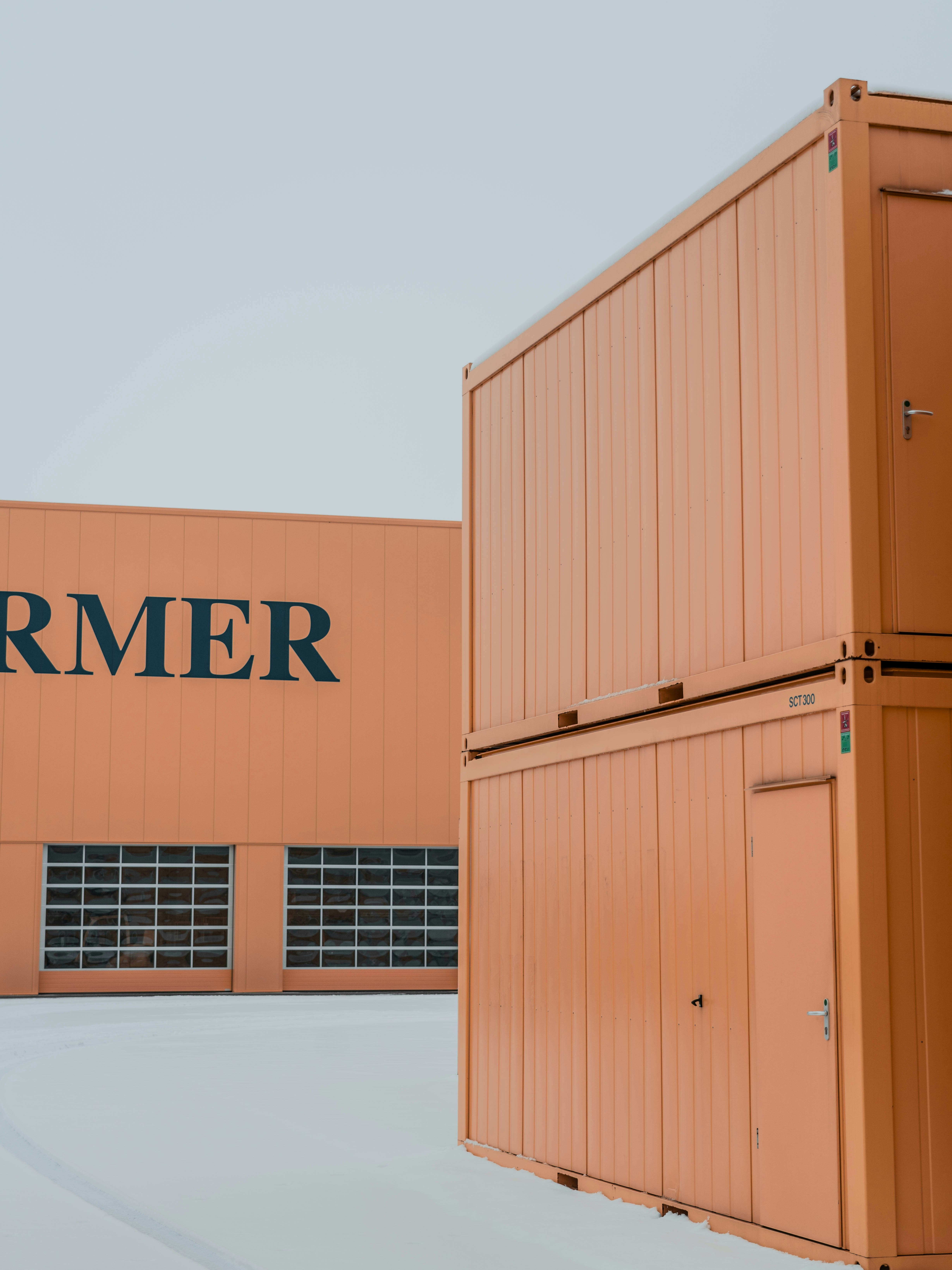 A large orange container sitting in front of a building photo – Free ...