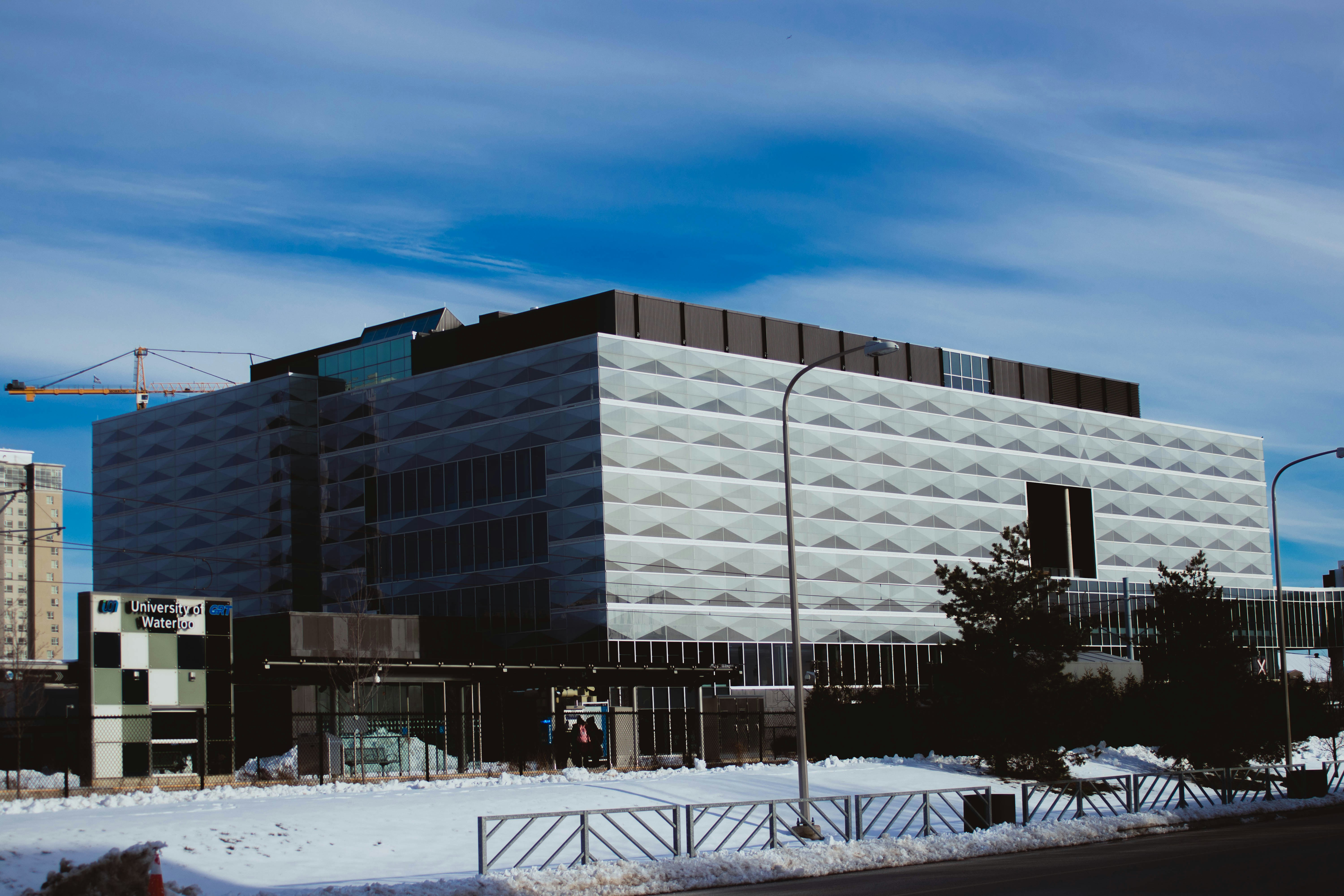 A contemporary building featuring a striking geometric facade, set against a clear blue sky with snow-covered ground in the foreground.