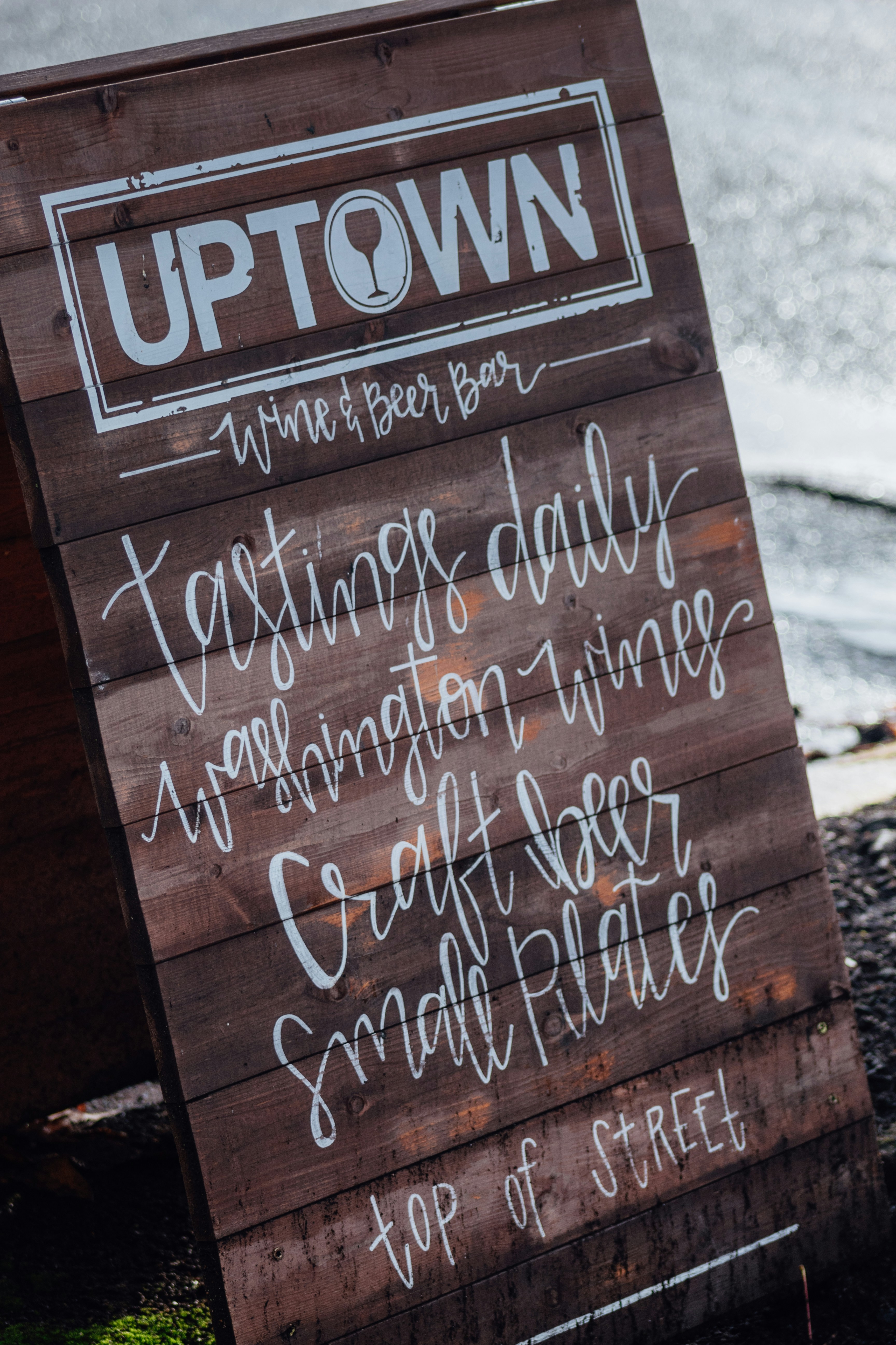 Uptown Chalkboard Sign: Daily Wine & Craft Beer Tastings on a Weathered Street Corner