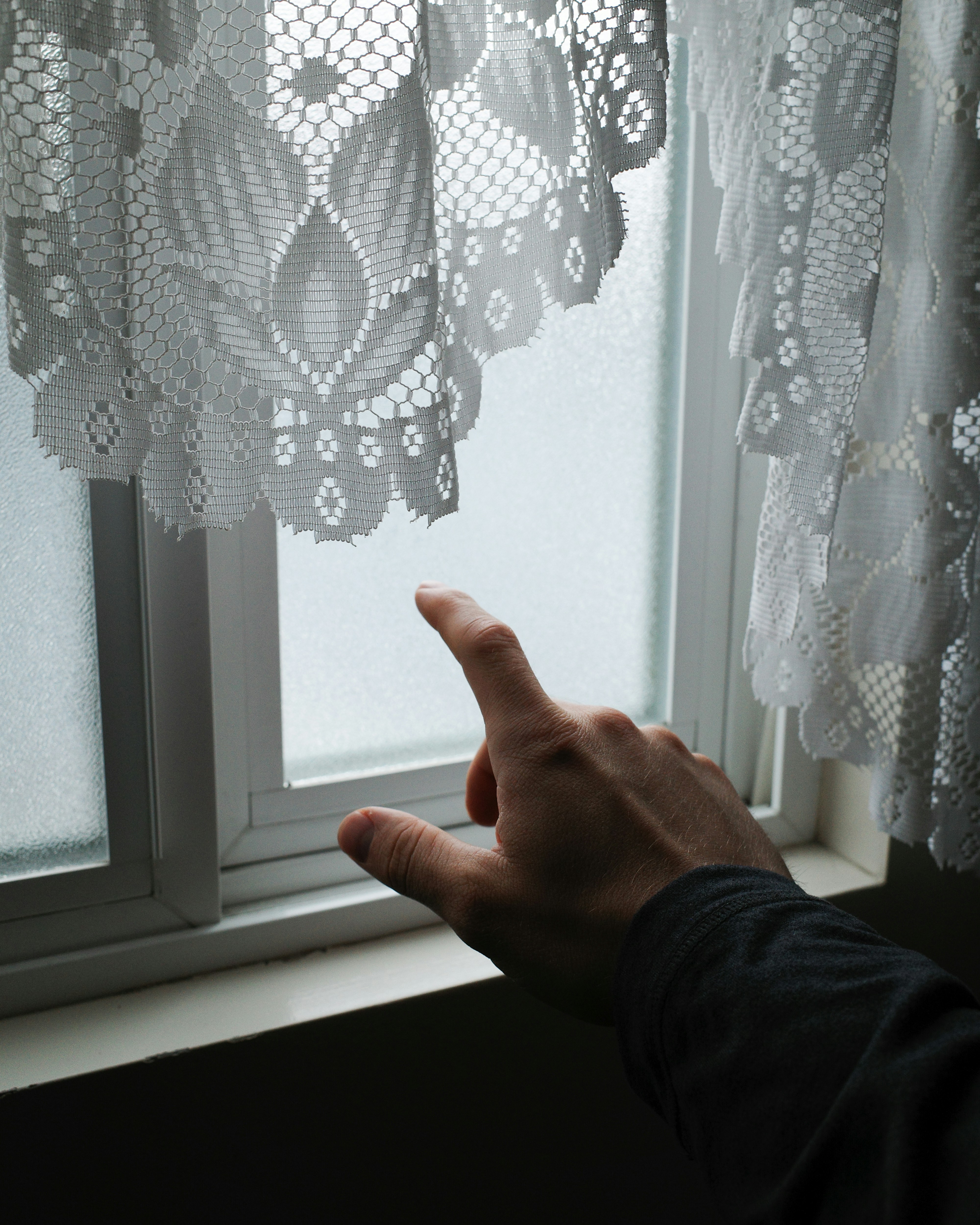 Touch of Light: A Hand Reaches Toward Lace by the Window
