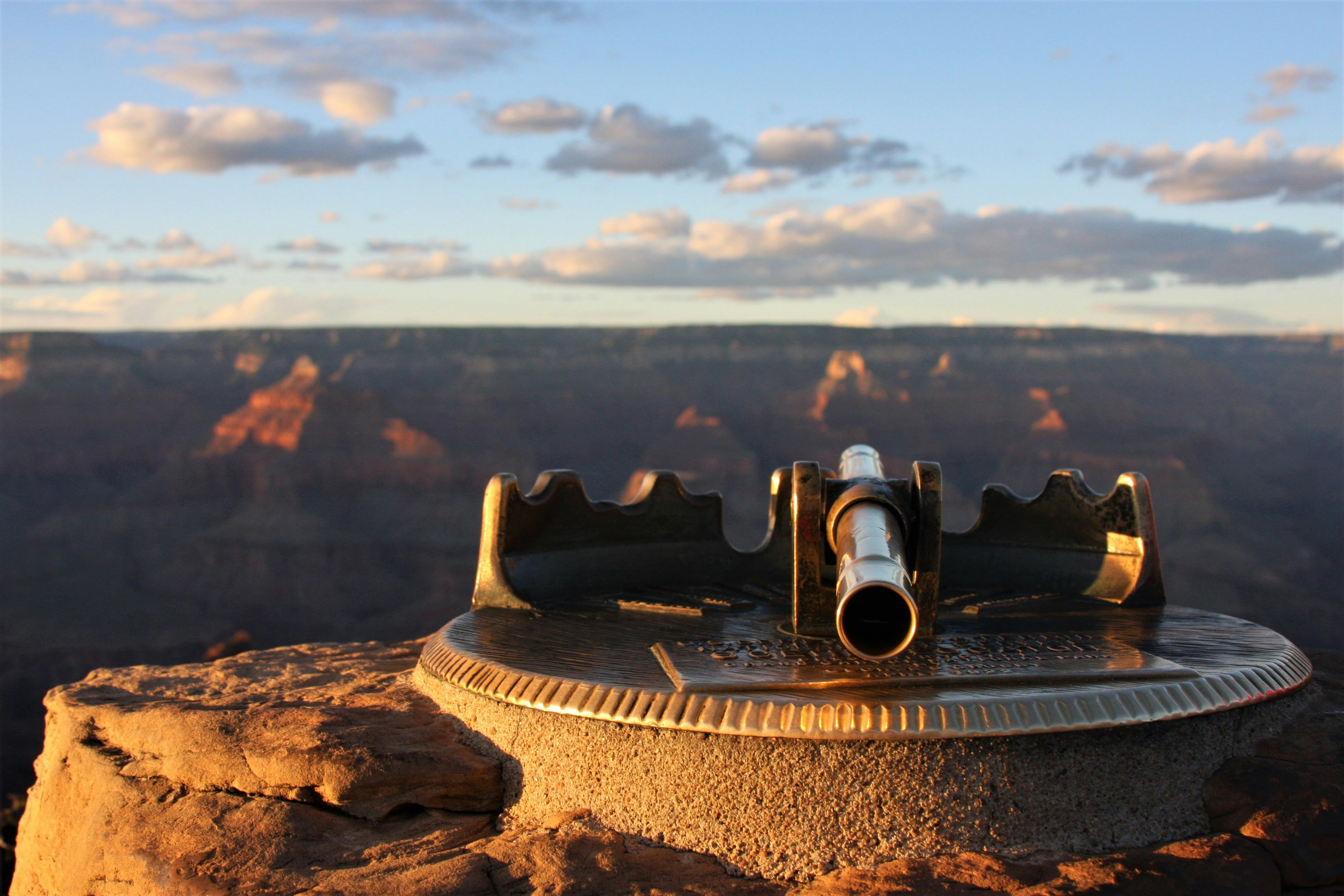 Viewing scope glistening in the setting sun against a vast canyon backdrop.