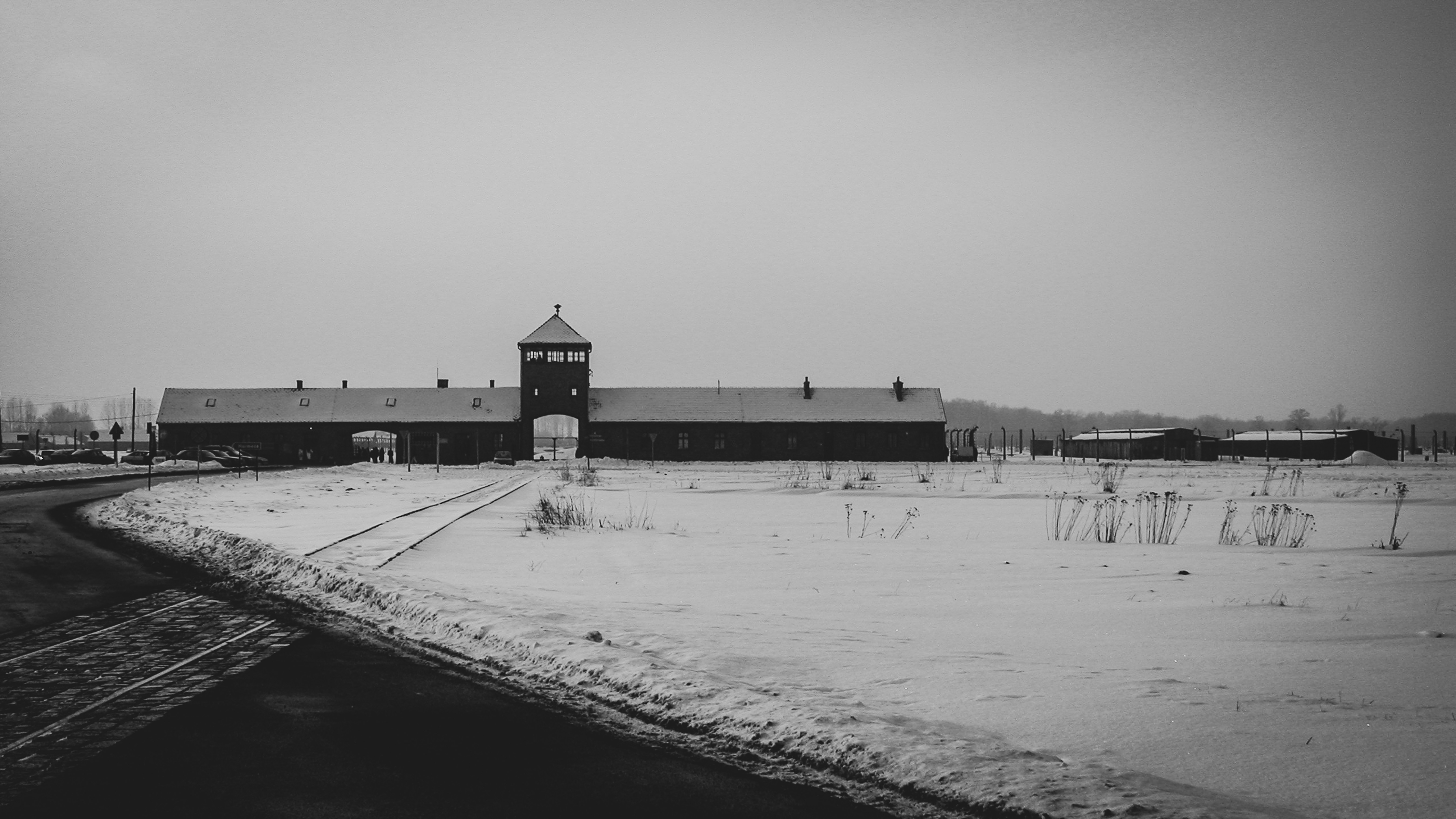Snow-covered building with a watchtower, surrounded by a barren landscape, evoking a sense of solemnity and reflection.