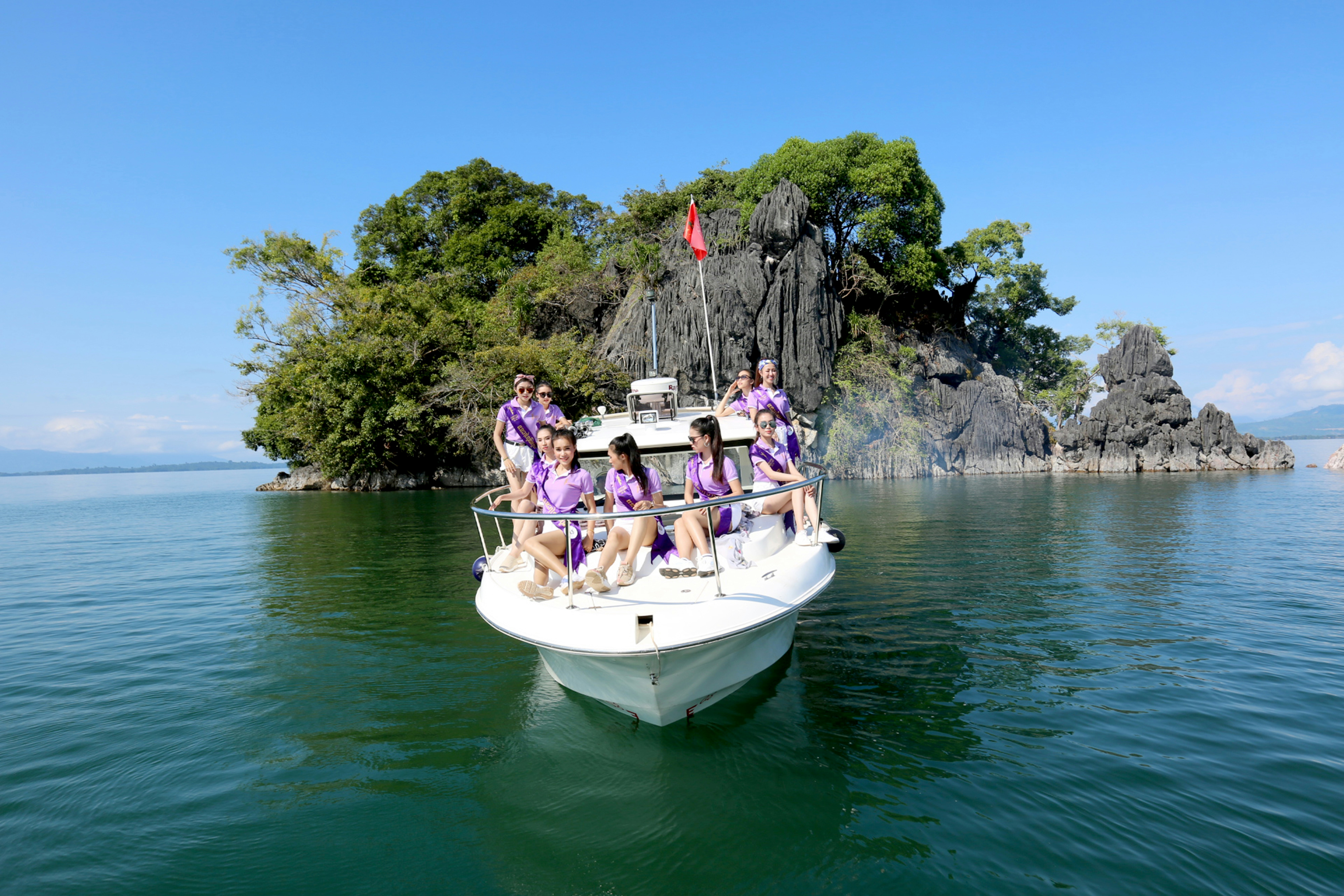 Sailboat Crew in Matching Purple Attire Anchored Against a Cliffside Isle