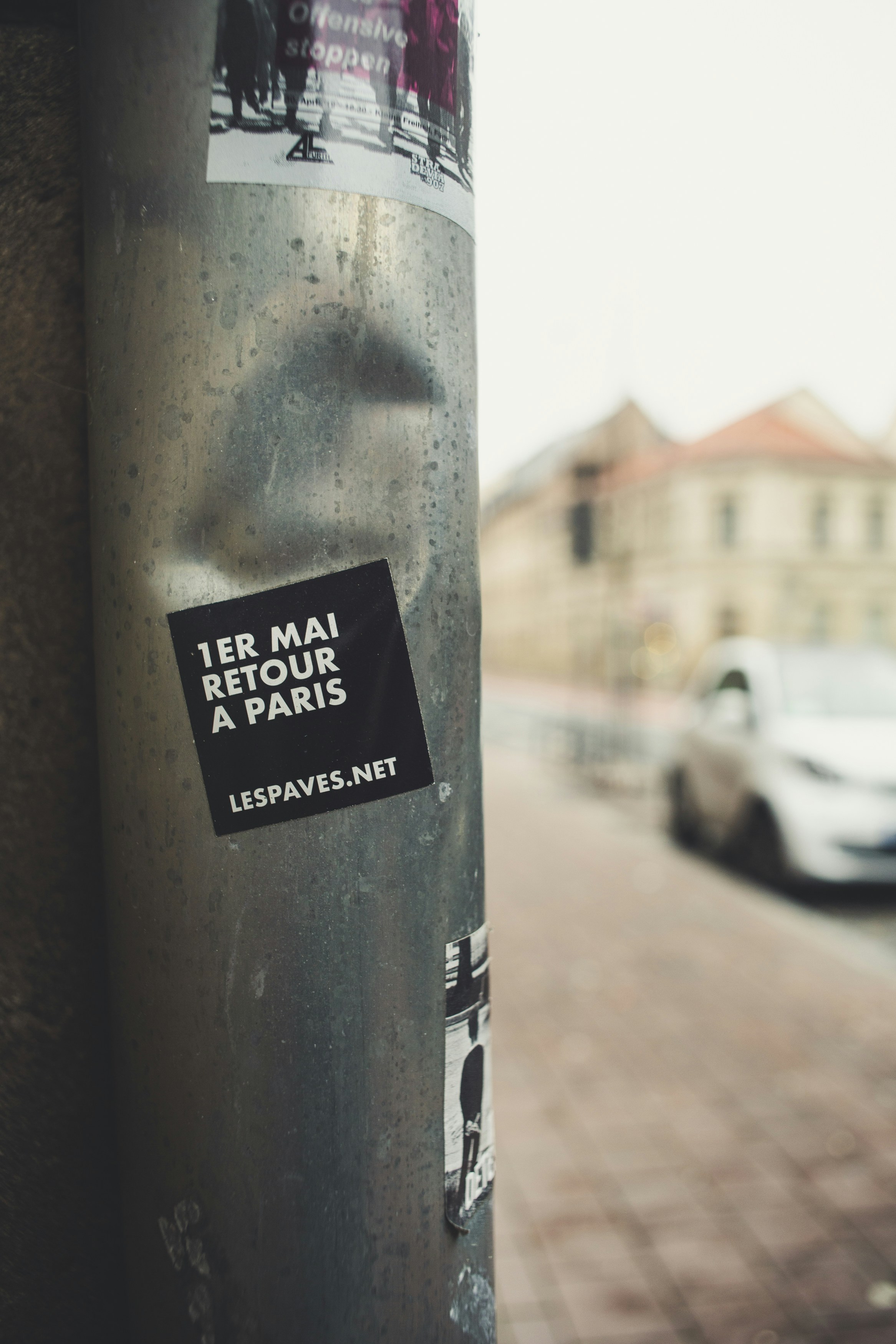 1ER MAI RETOUR A PARIS: Sticker on a Weathered Parisian Pole
