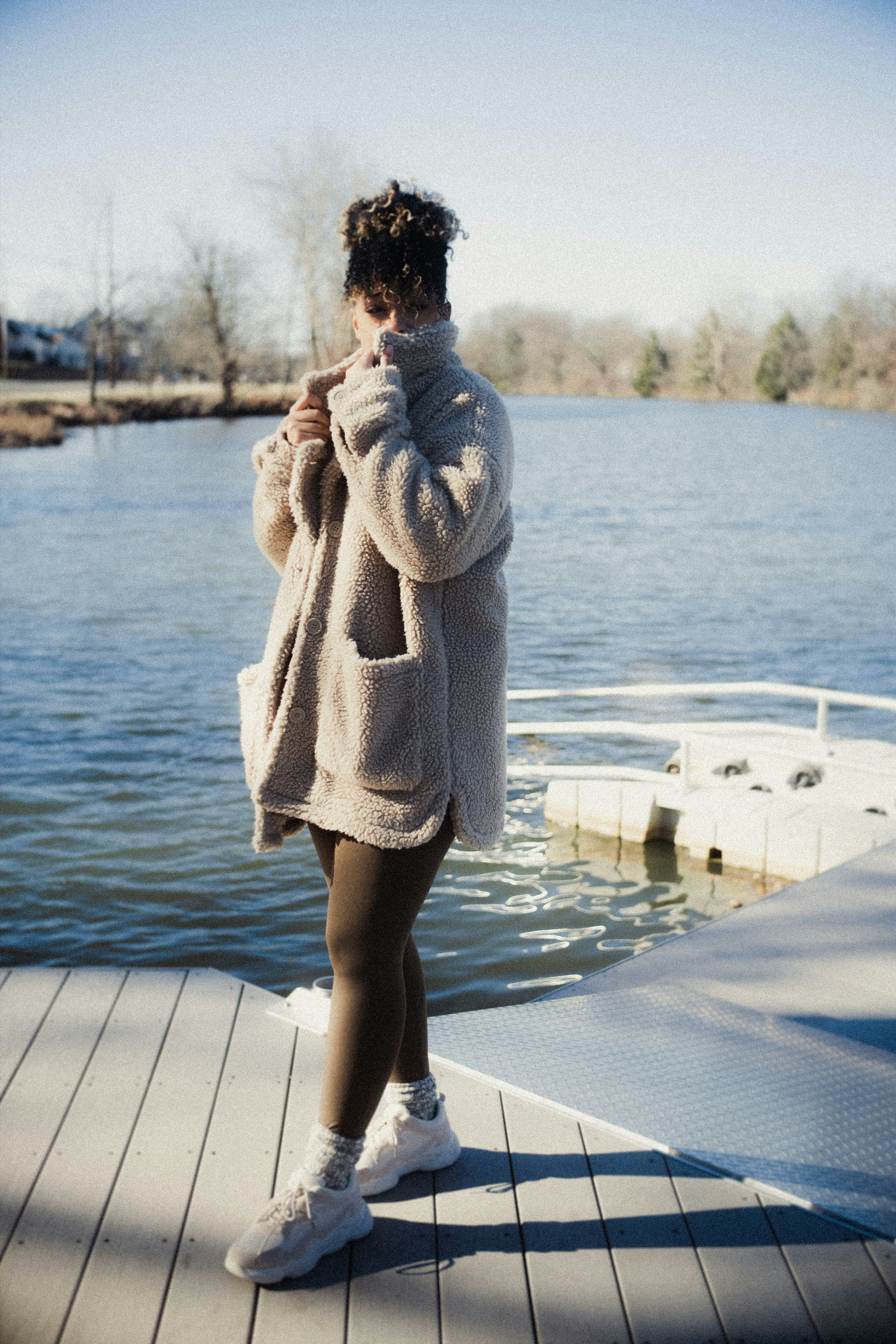 woman in brown coat standing on dock during daytime