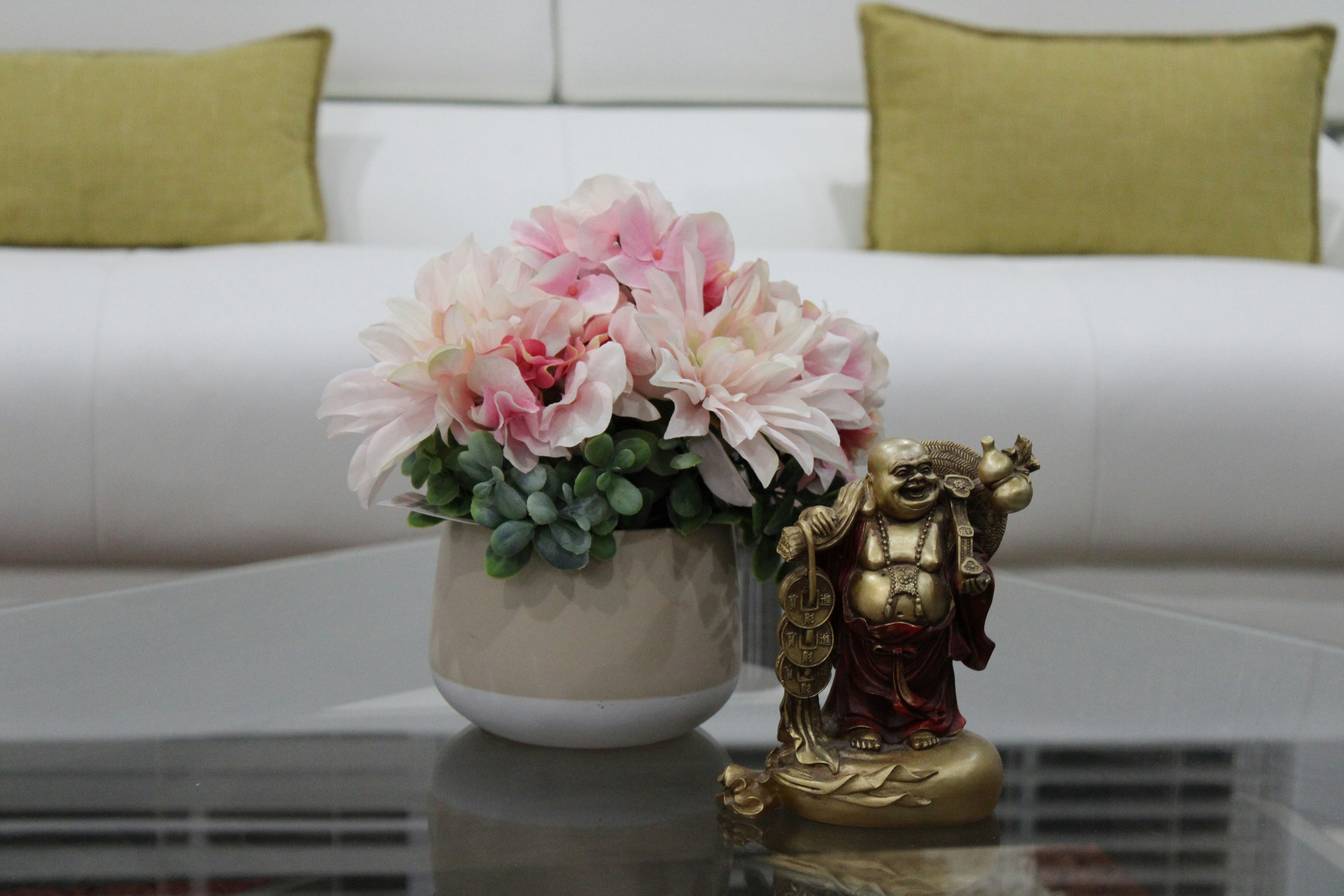 Blooming centerpiece and laughing Buddha on glass table