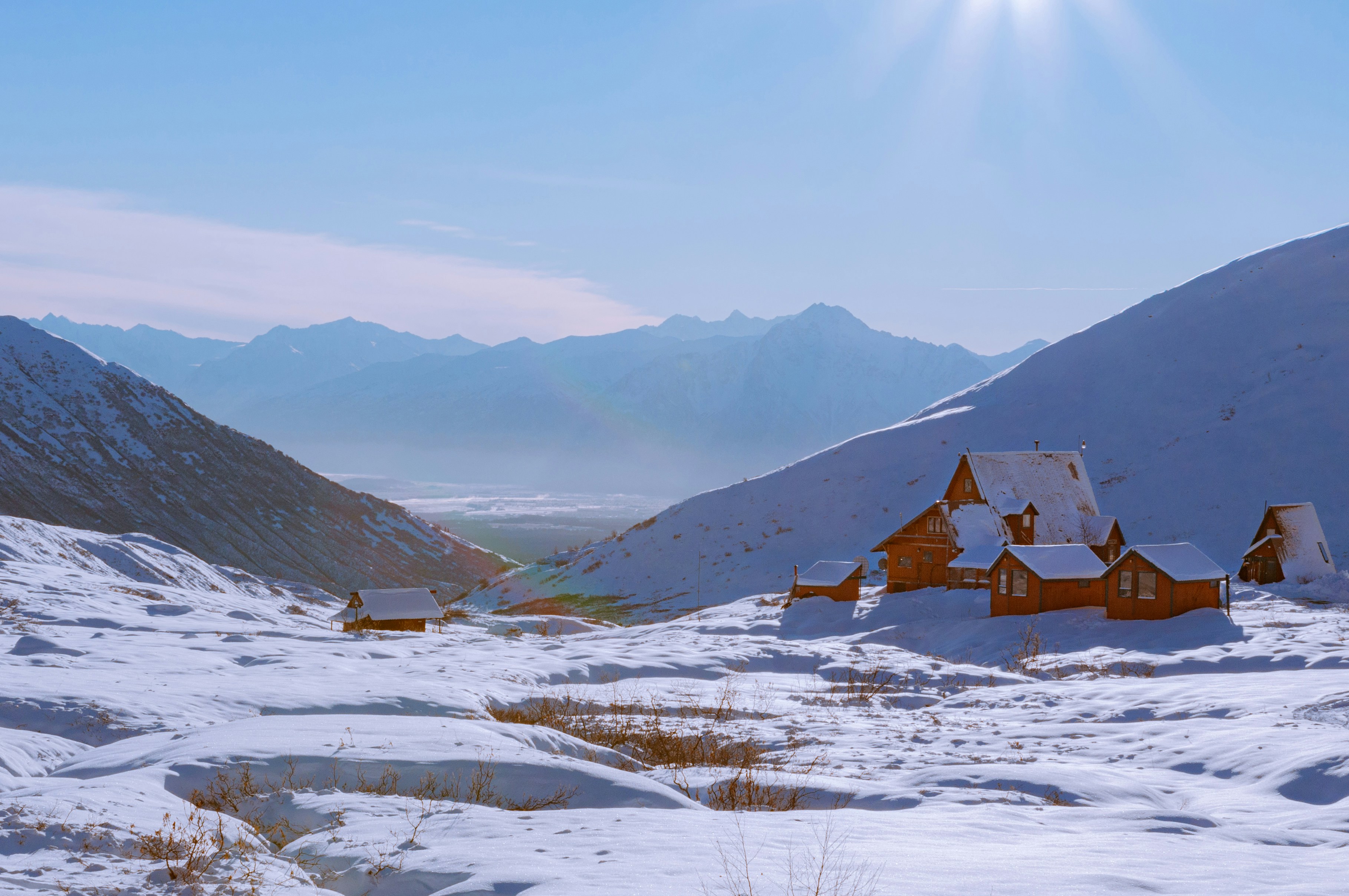 brown wooden house on snow covered ground near mountains during daytime