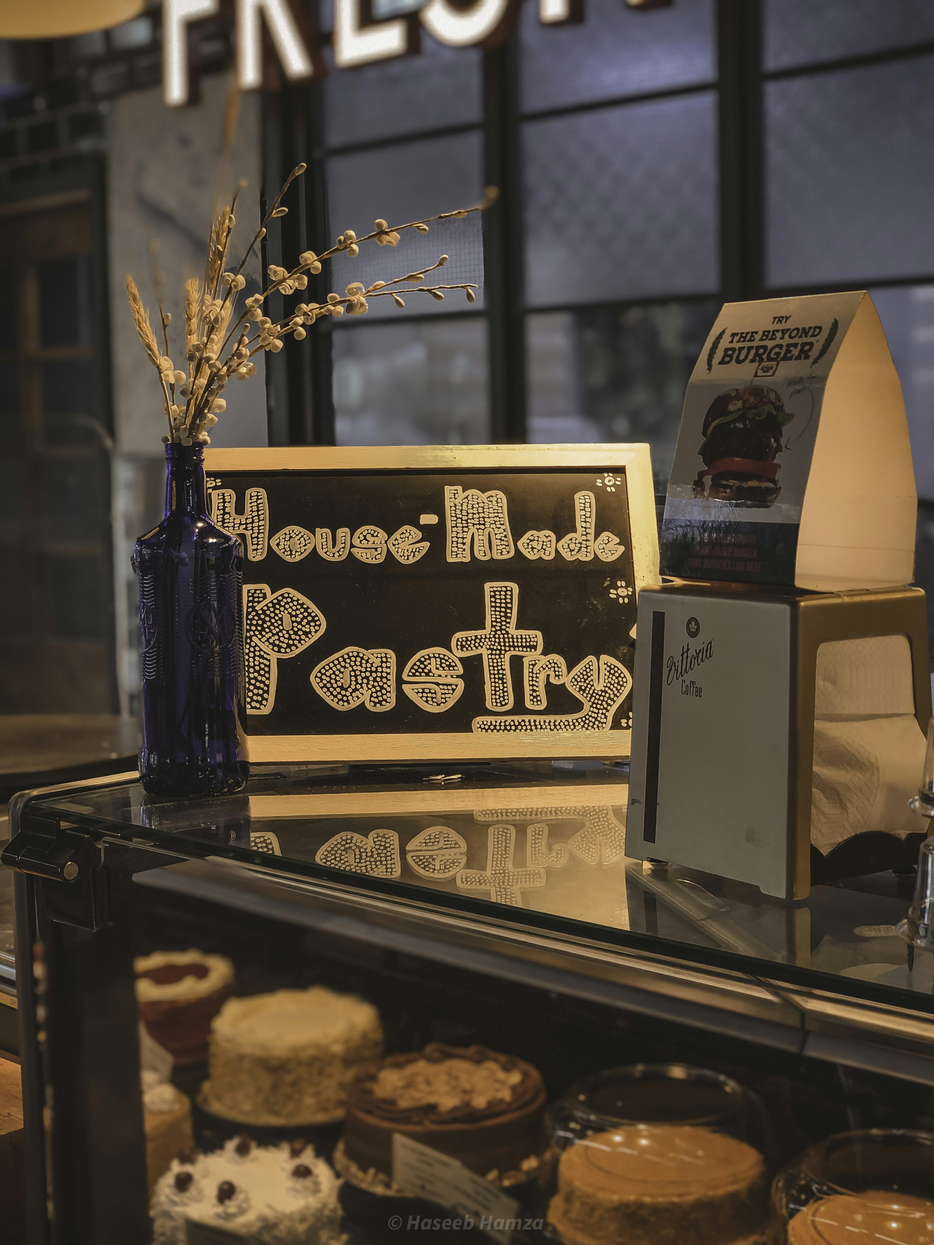 House-Made Pastry Signage Framed by a Blue Vase in a Cozy Café Display