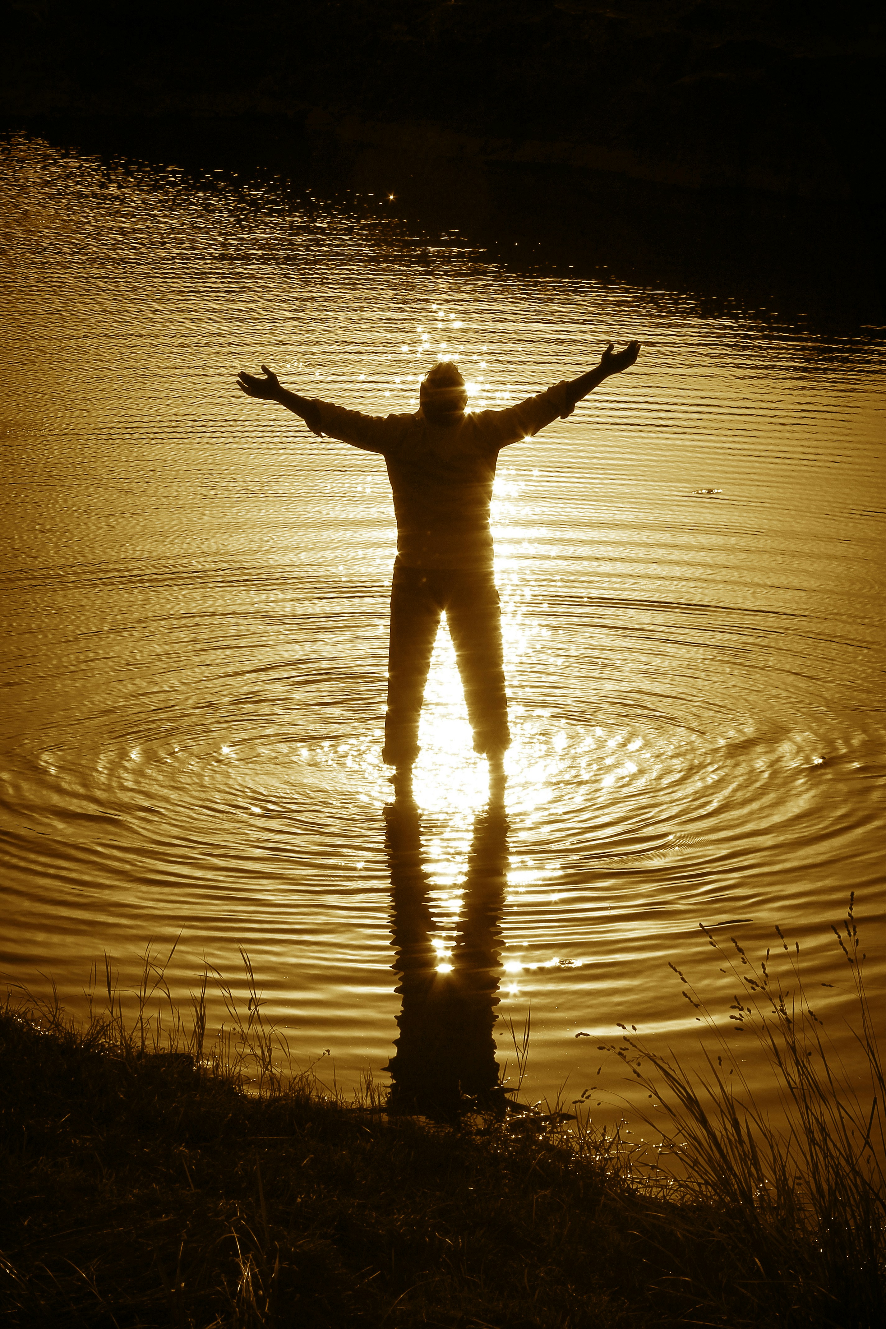 Golden Hour Embrace: Silhouette Reaching Toward Light Across Rippling Water