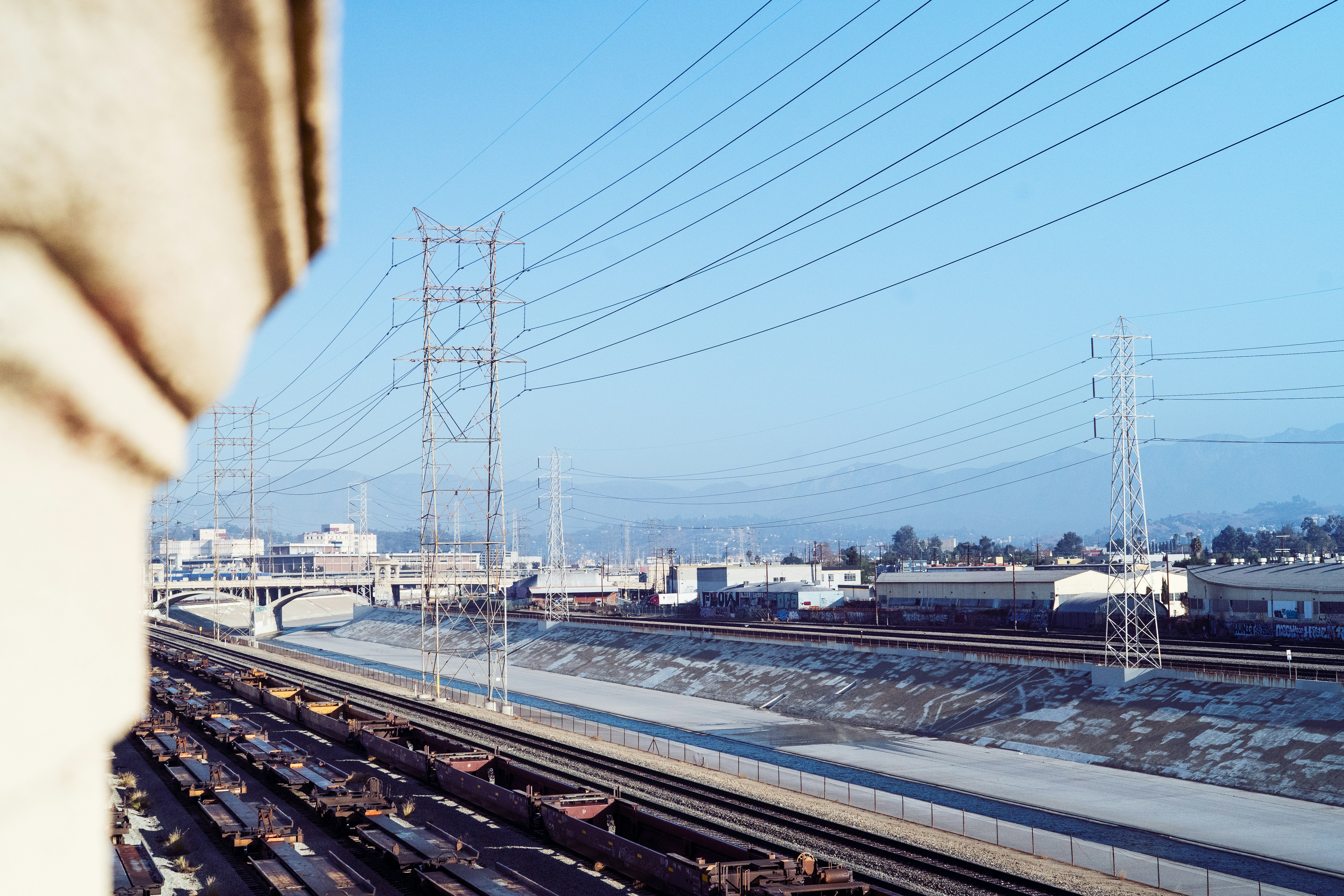 A panoramic view of industrial rail yards and power lines under a clear blue sky, highlighting the intricate patterns of urban infrastructure.