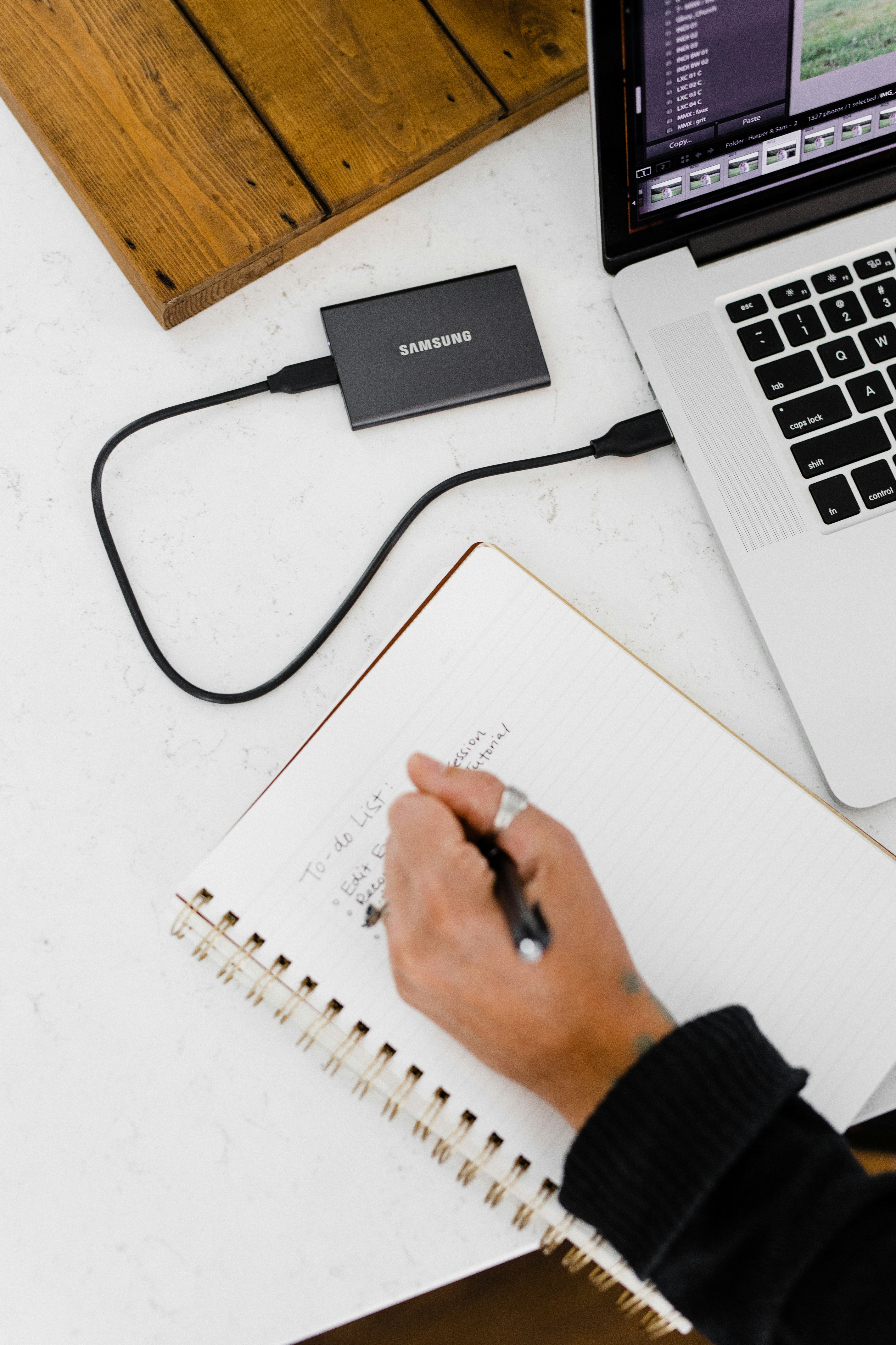 Person writing on white paper beside macbook pro photo – Free Business ...