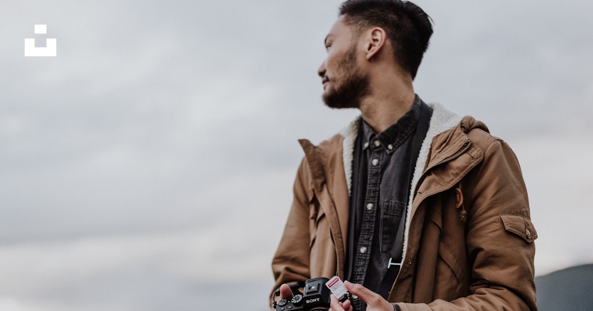 Foto Hombre Con Chaqueta Marrón Sosteniendo Una Cámara Dslr Negra