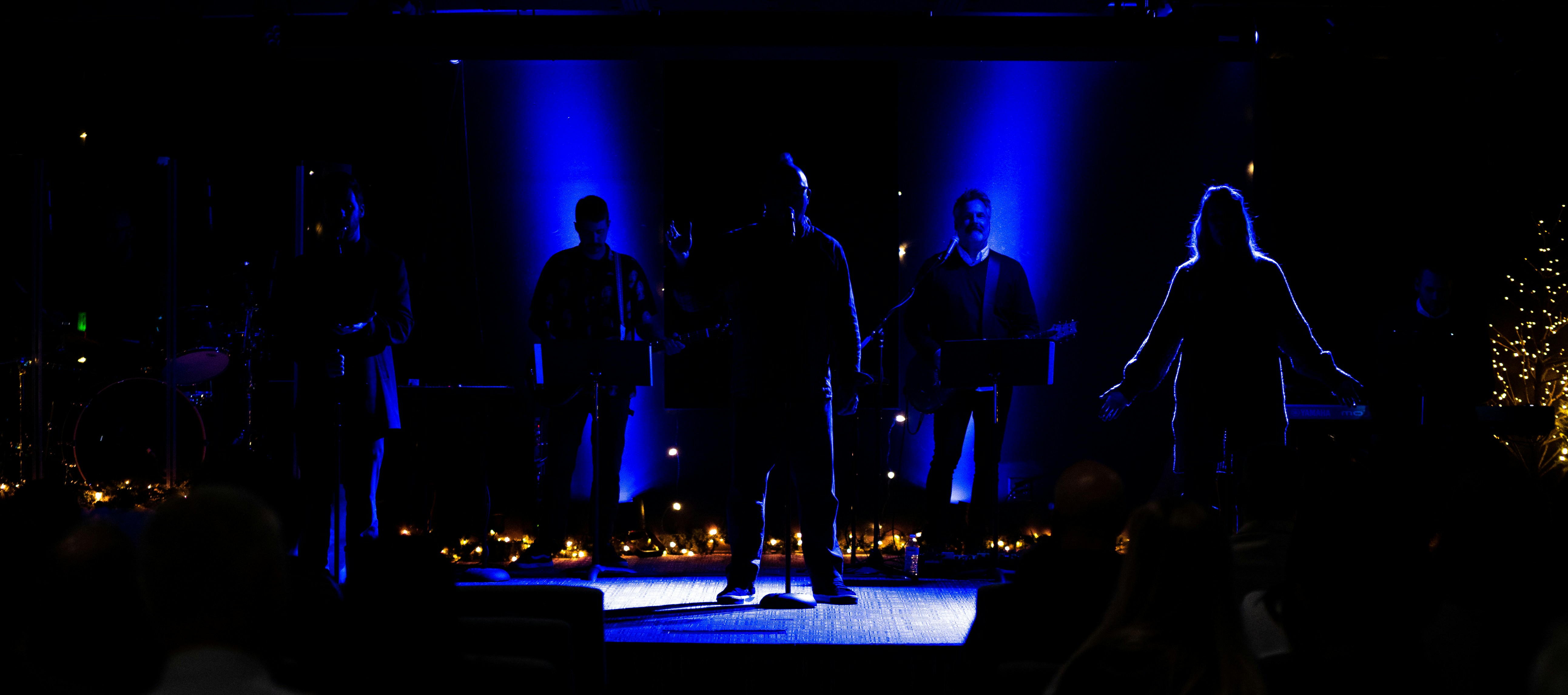 Center Spotlight in Blue: A Quiet Moment Behind Silhouettes
