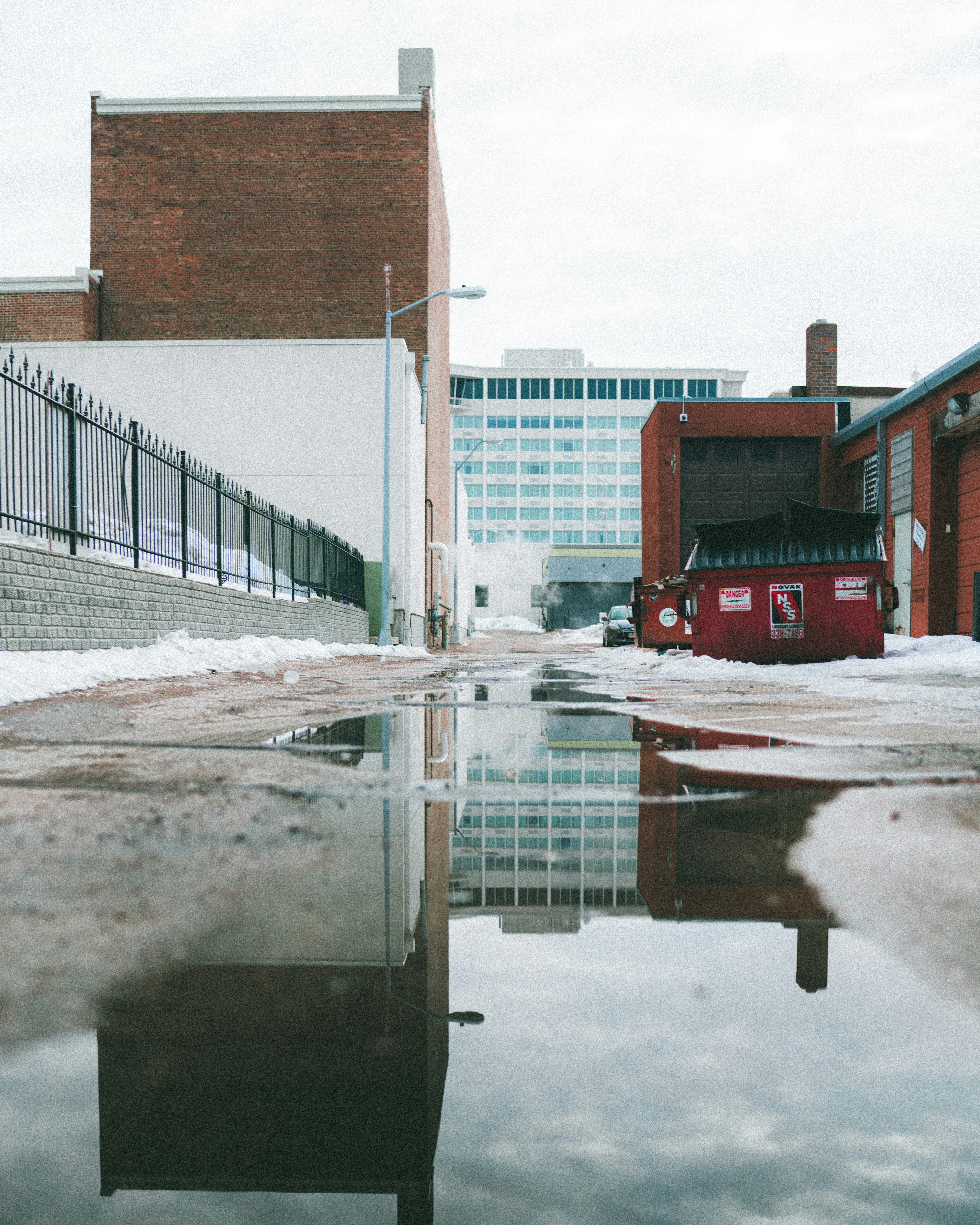 Midwinter Mirror: The Alleyway's Puddle Portrait of Brick and Sky
