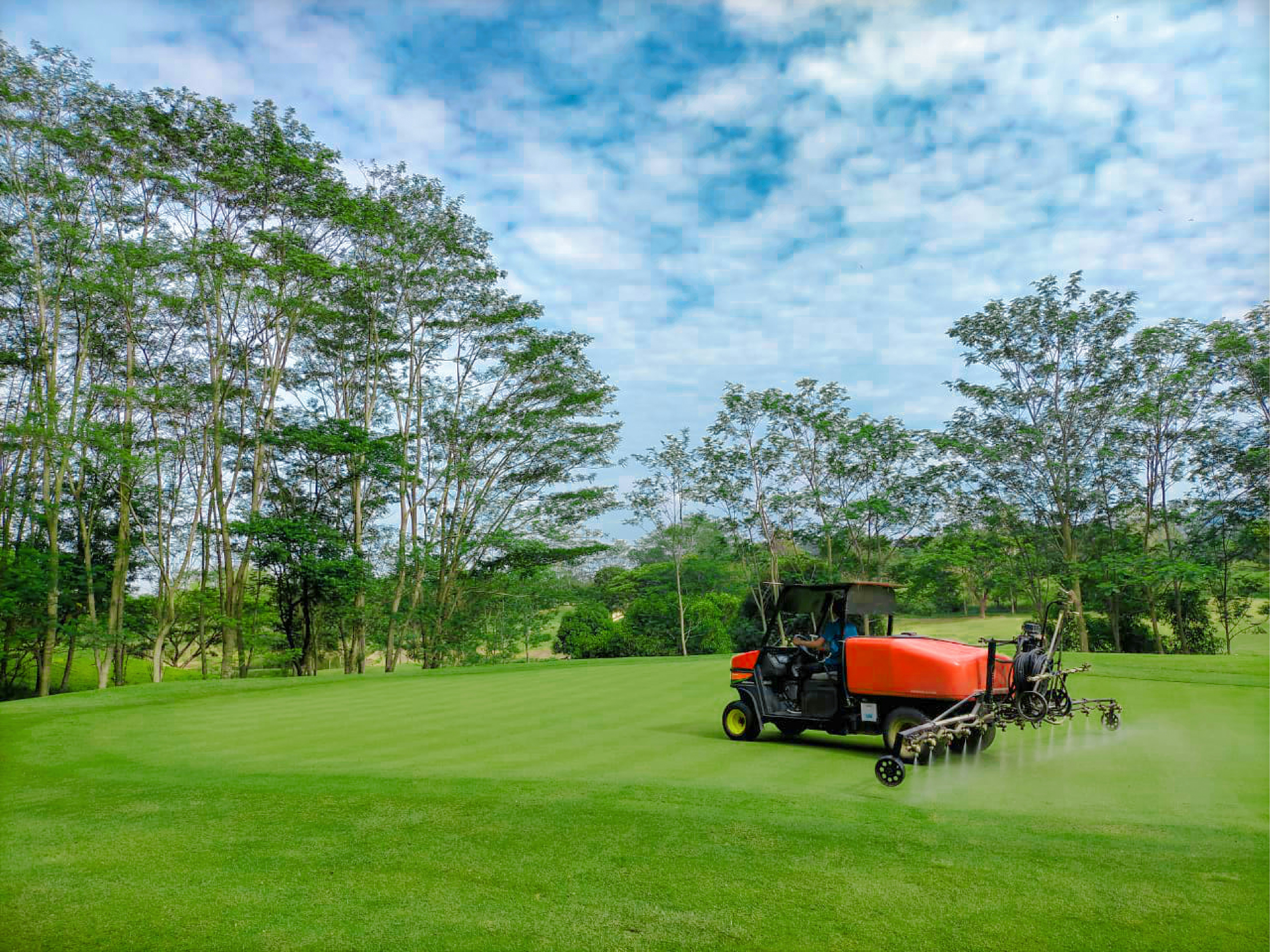 A tractor is spraying the grass on a golf course photo – Free Plant ...