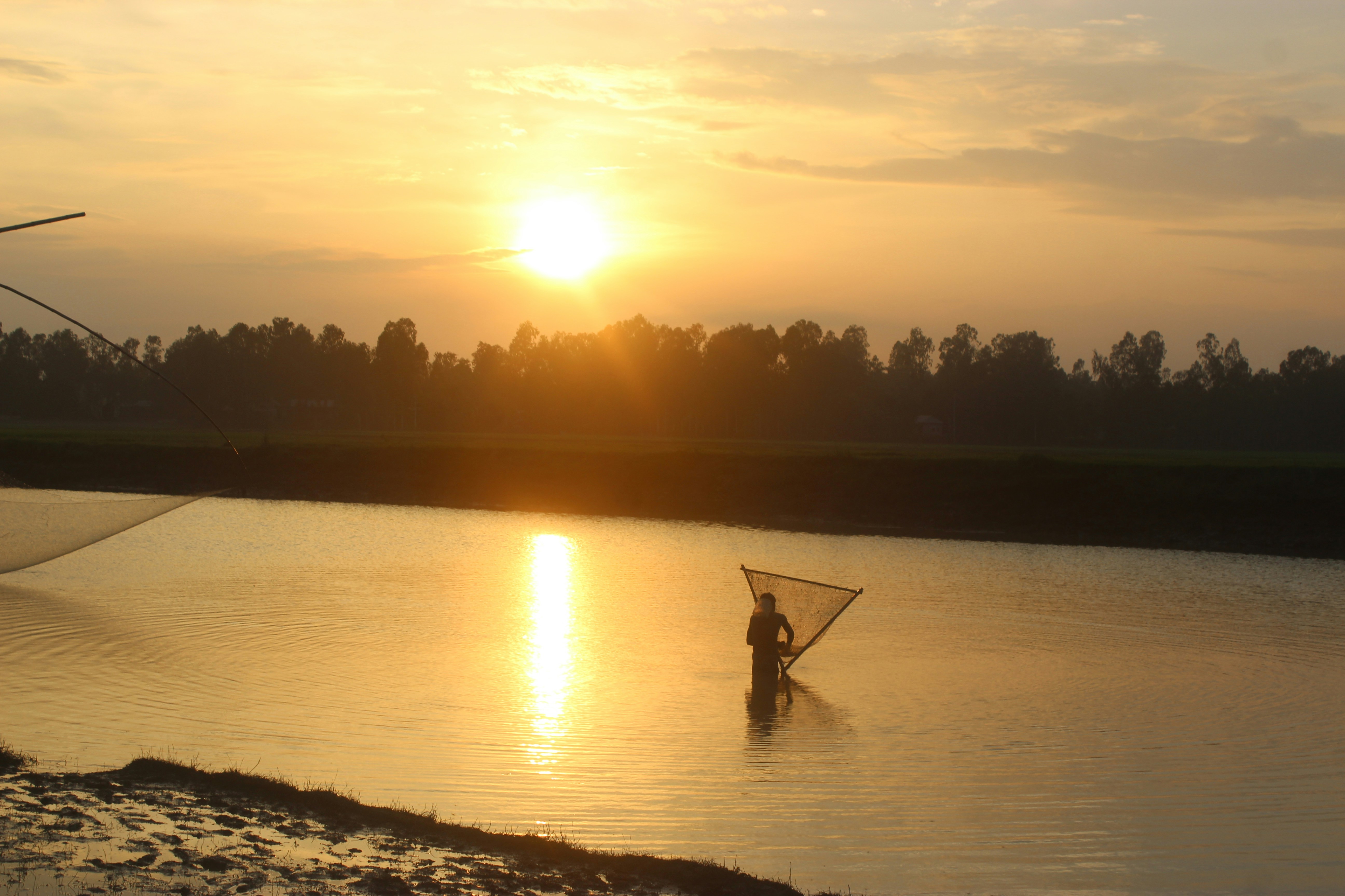 Silhouetted figures on a boat glide across the sea under a vibrant sunset sky.