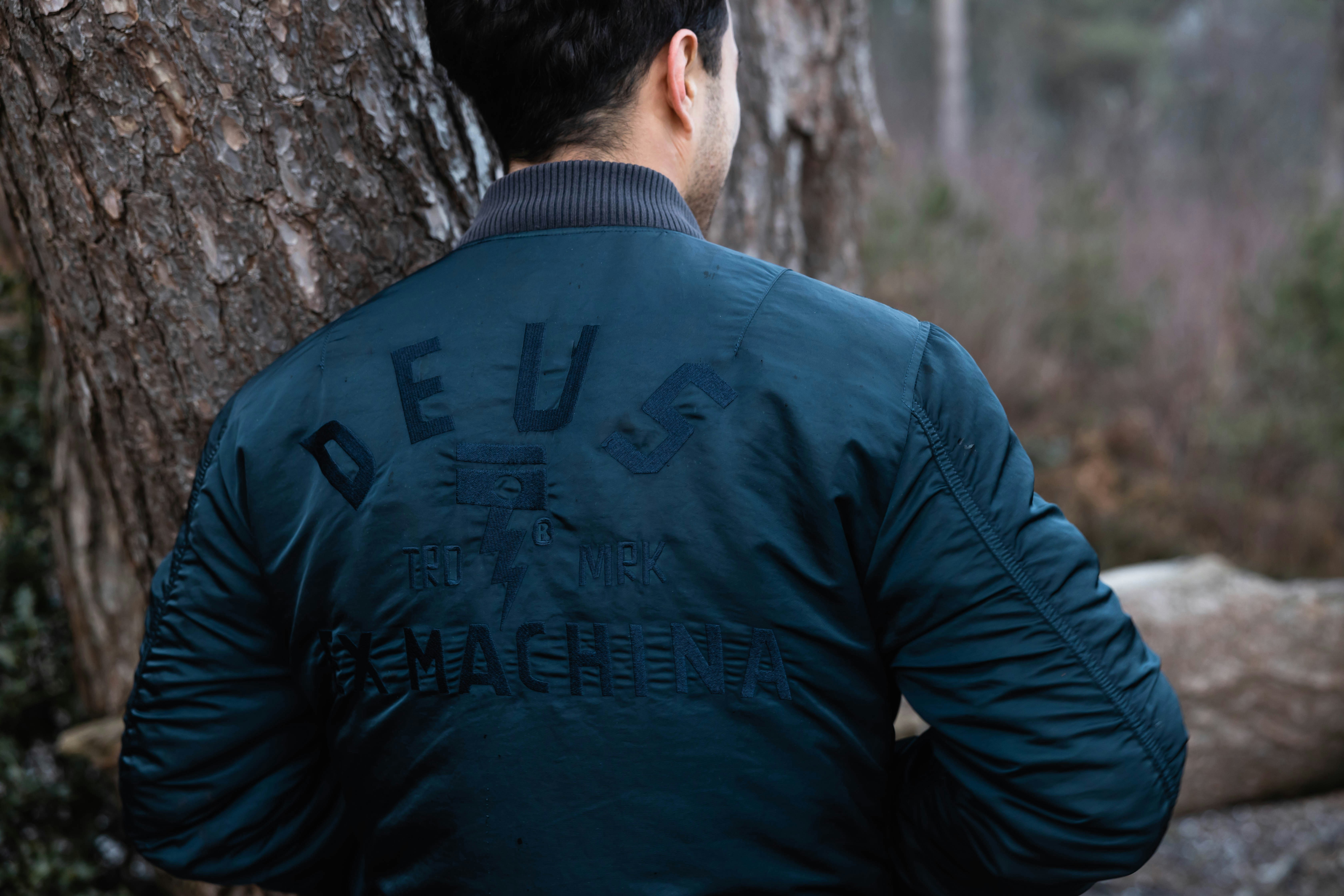 A man wearing a blue bomber jacket on an outdoor walk in a forest