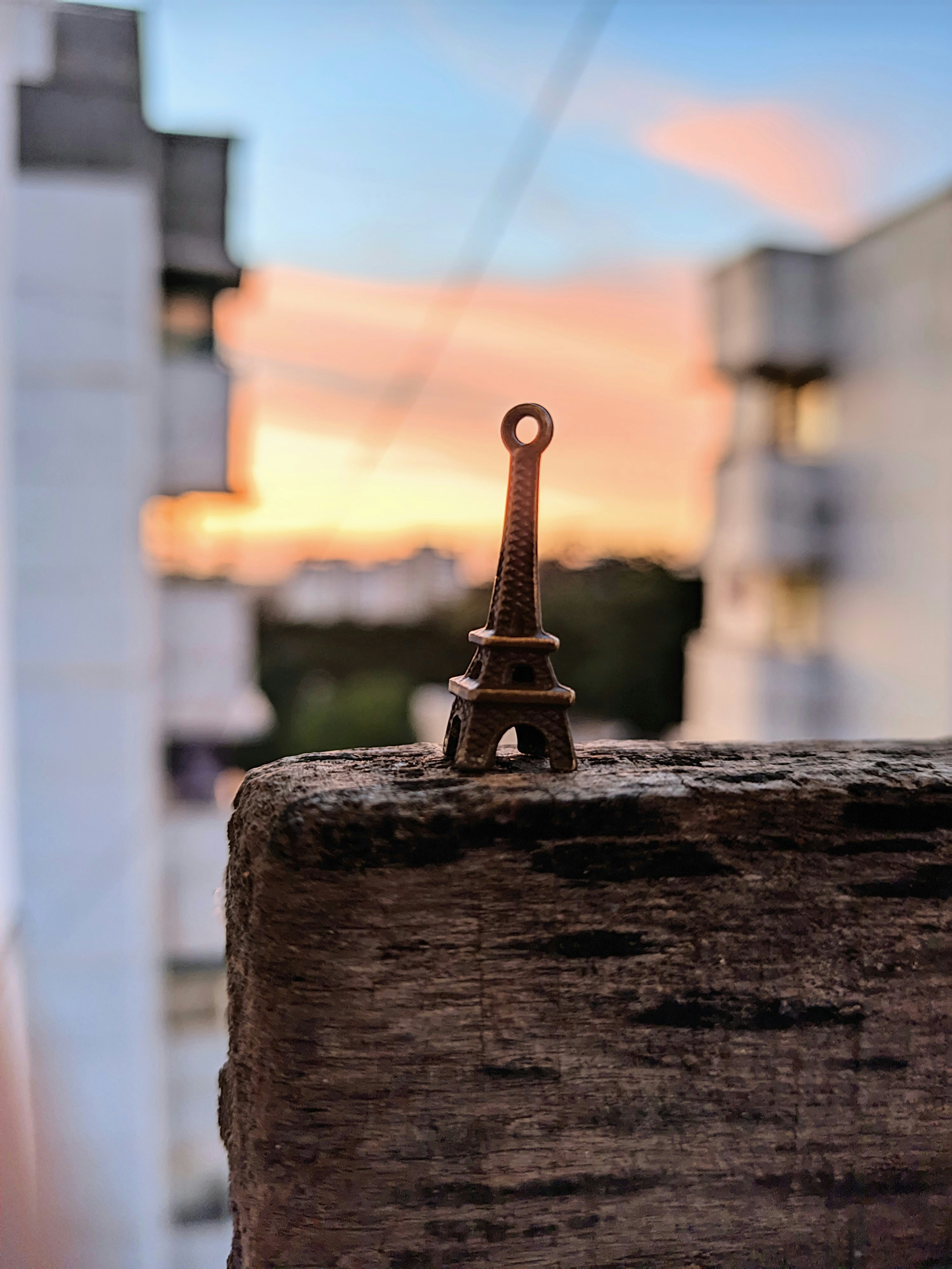Sunset micro-sculpture: a tiny Eiffel Tower on weathered wood