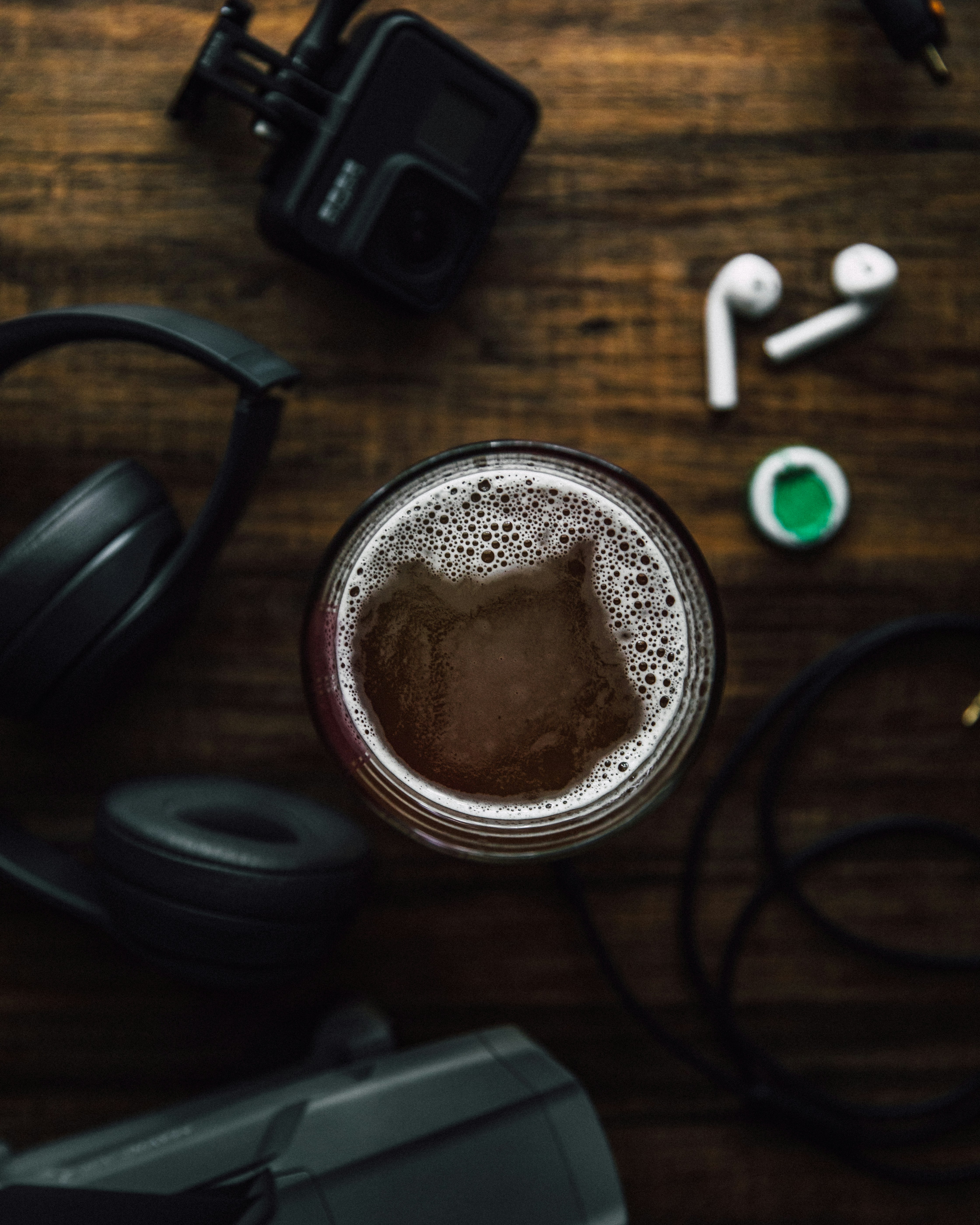 Cold fresh home brew beer on desk with camera gear and headphones