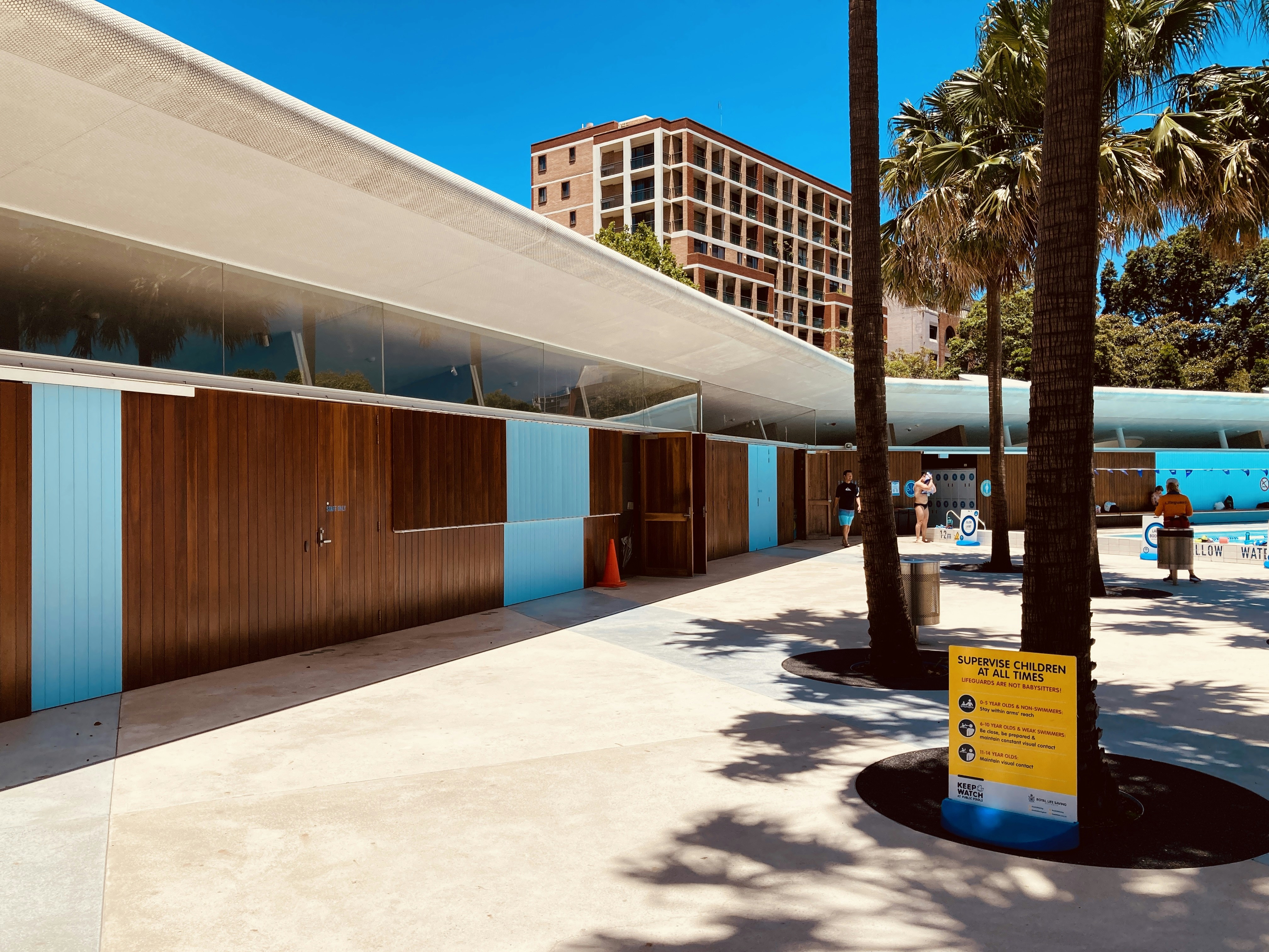Blue-Washed Facade, Palm Shadows, and a Quiet Poolside Walkway