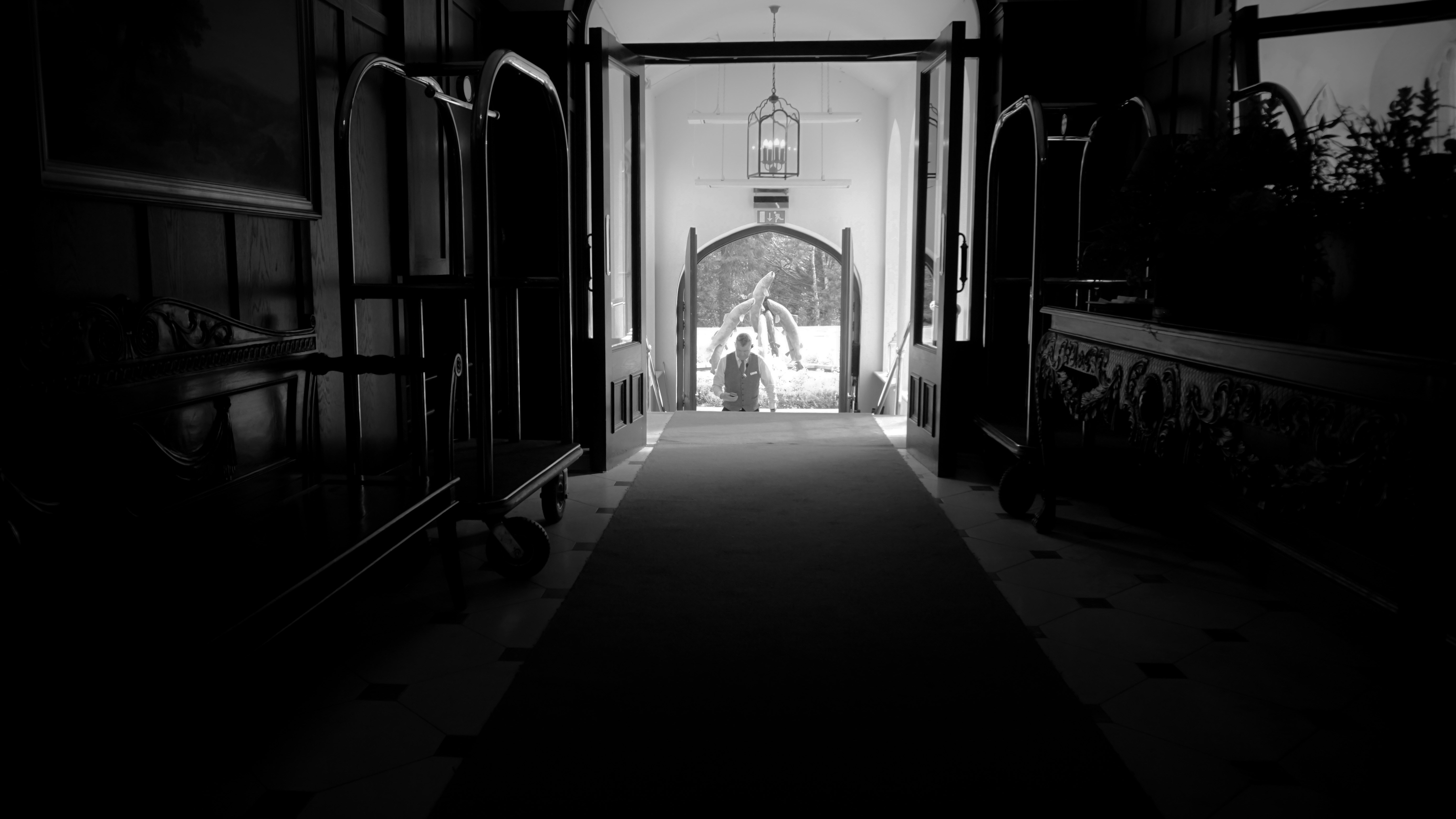 A dimly lit corridor leading to an ornate doorway, capturing the interplay of light and shadow in a historic setting.