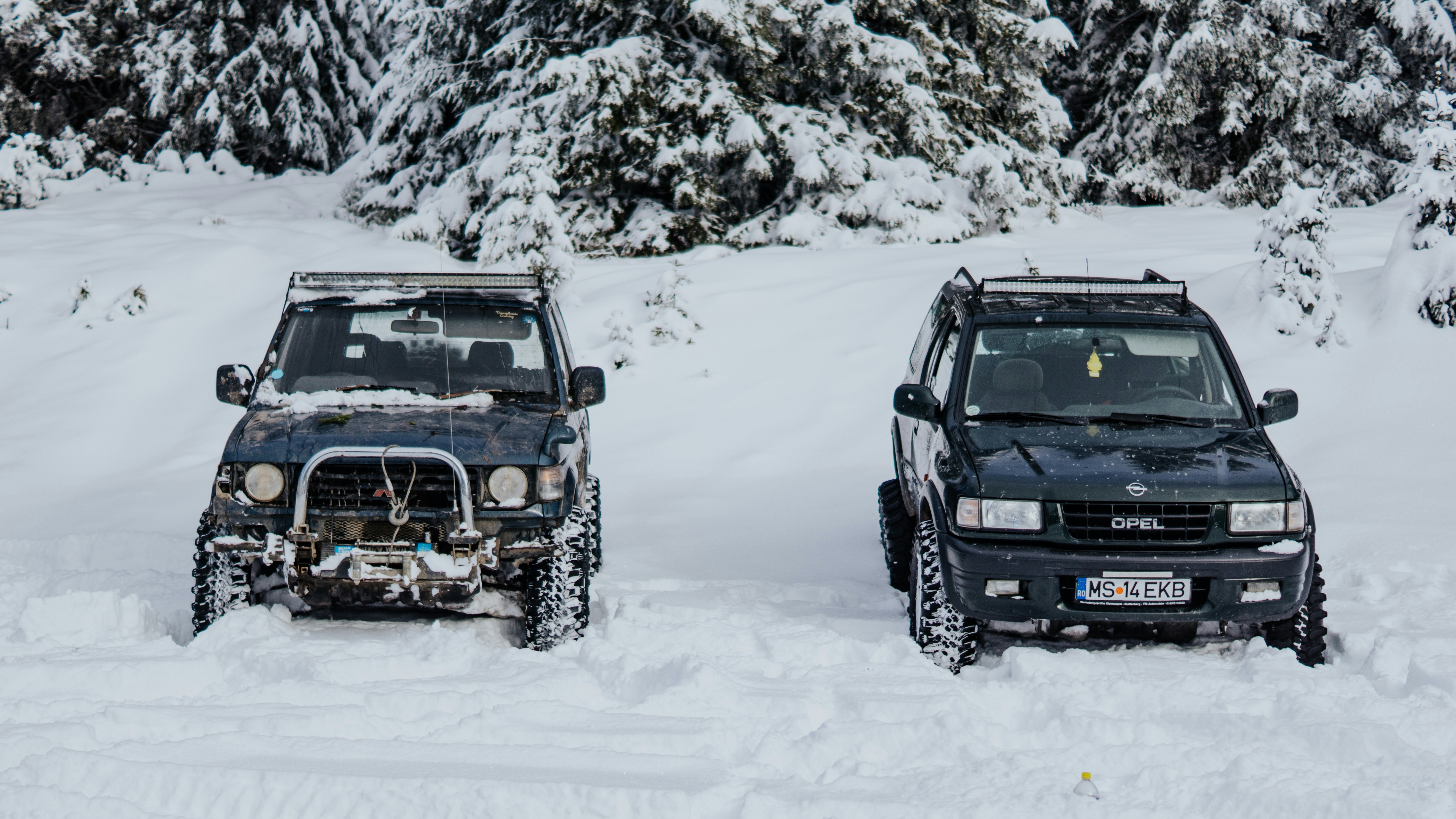 Two rugged SUVs parked side by side in a snowy landscape, showcasing their resilience against the elements.