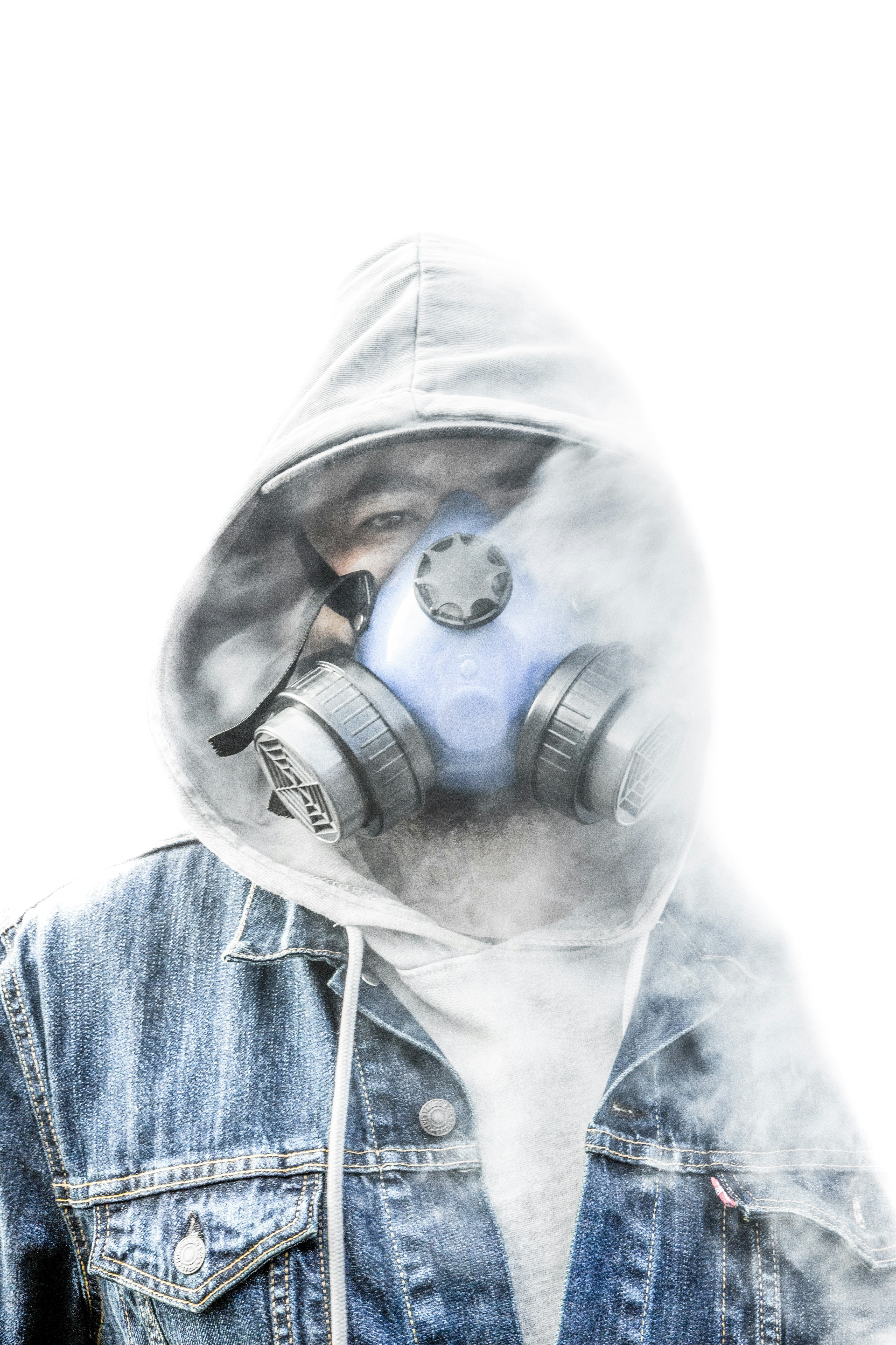 A masked individual shrouded in smoke, wearing a blue respirator and a grey hoodie, conveys a sense of intrigue and tension.