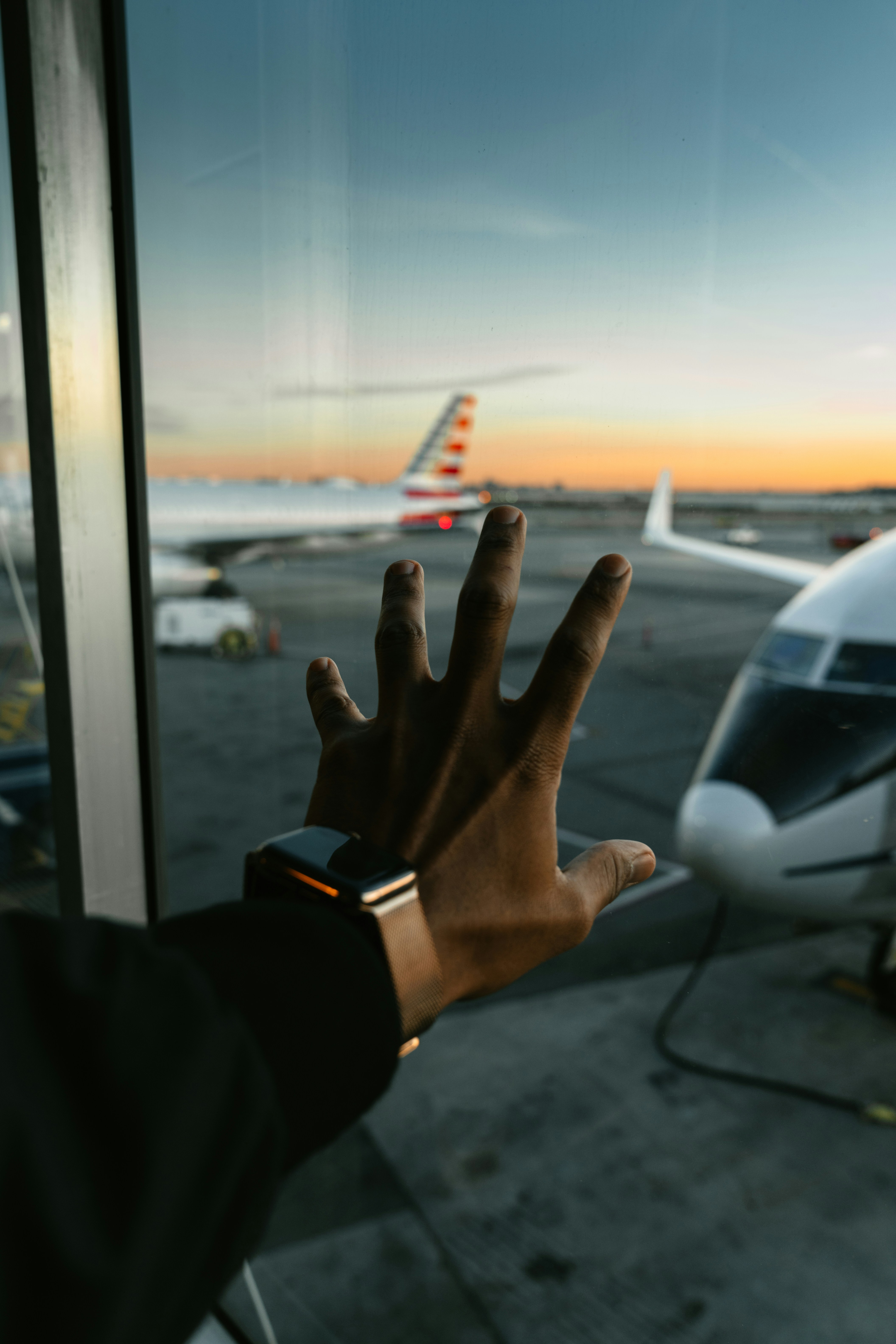 Touch at the Gate: A Hand Reaches Toward the Tarmac at Sunset