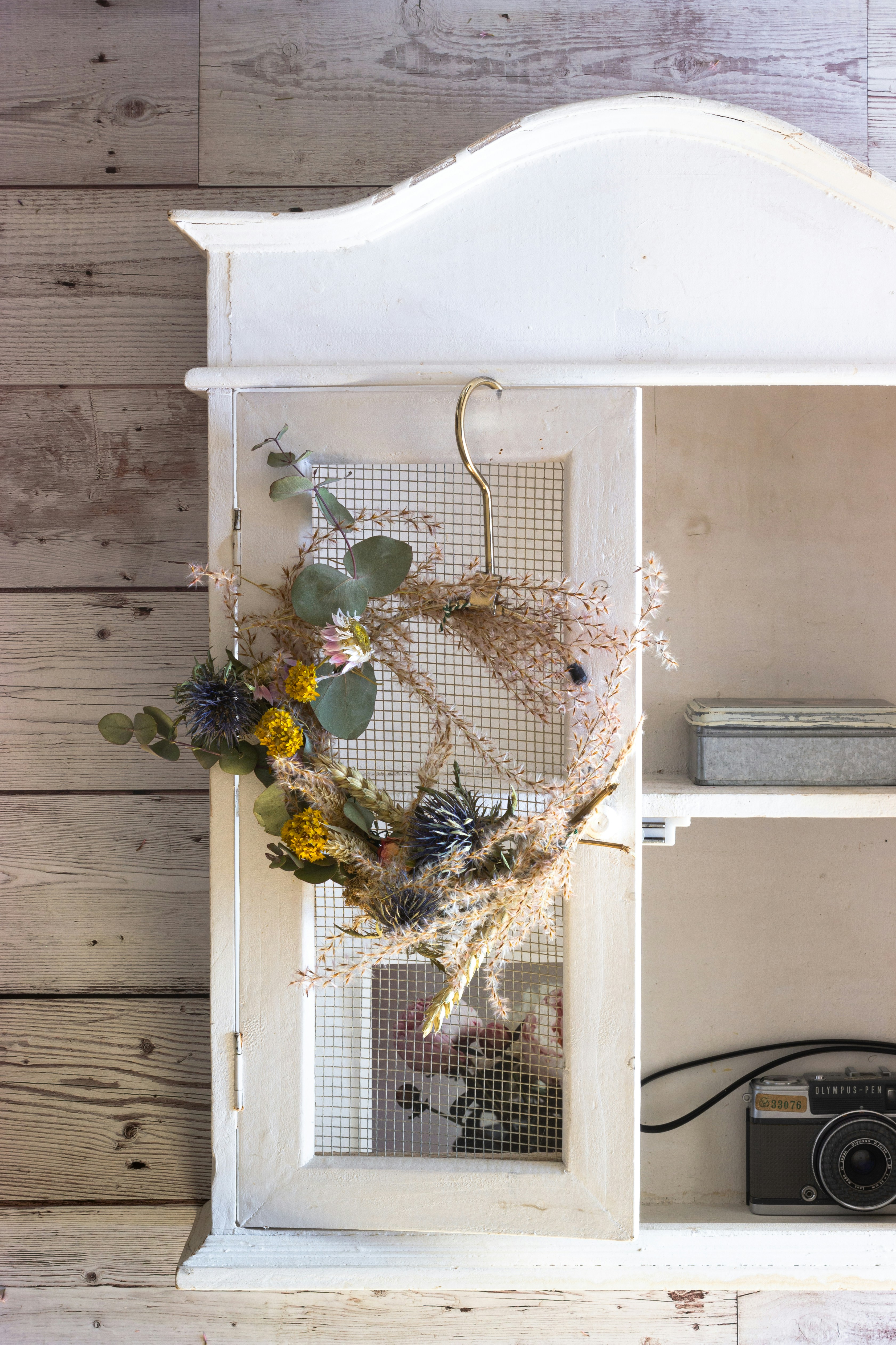 A Rustic Wall Shelf Adorned with a Dried Floral Wreath