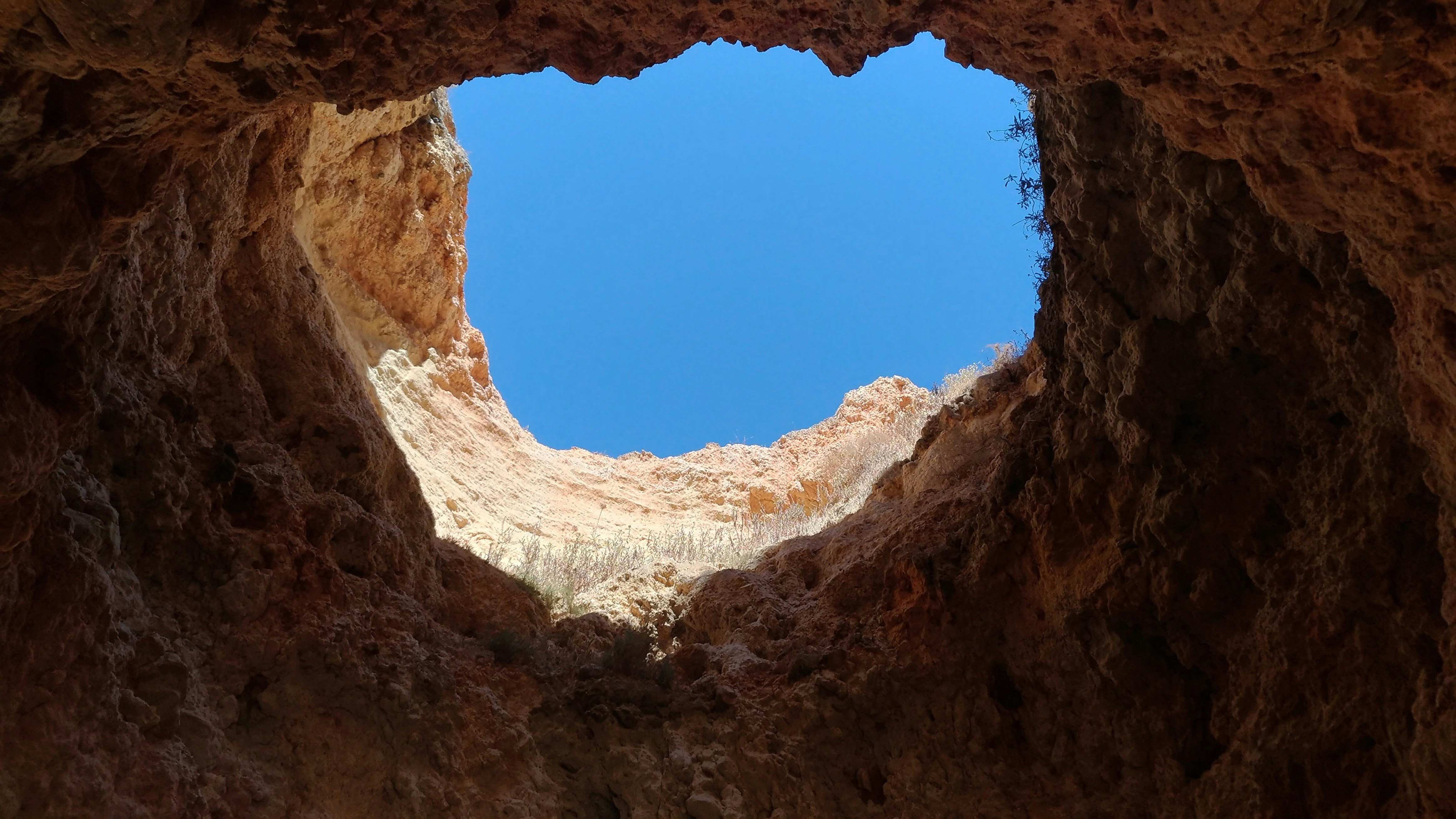 Circular rock formation frames a vibrant blue sky, highlighting contrasting textures.