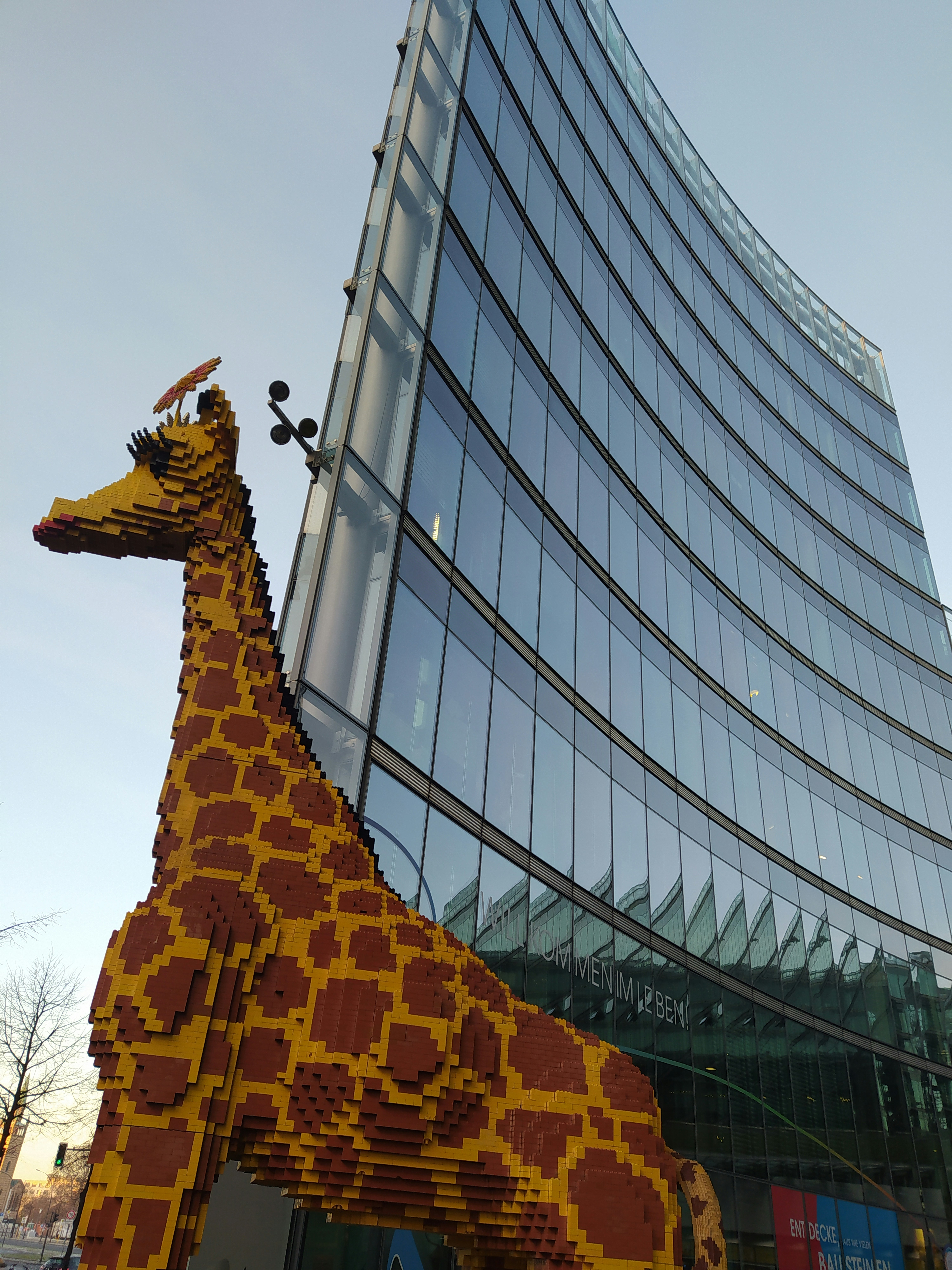 Blocky Giraffe Beside a Glass-Curved Facade