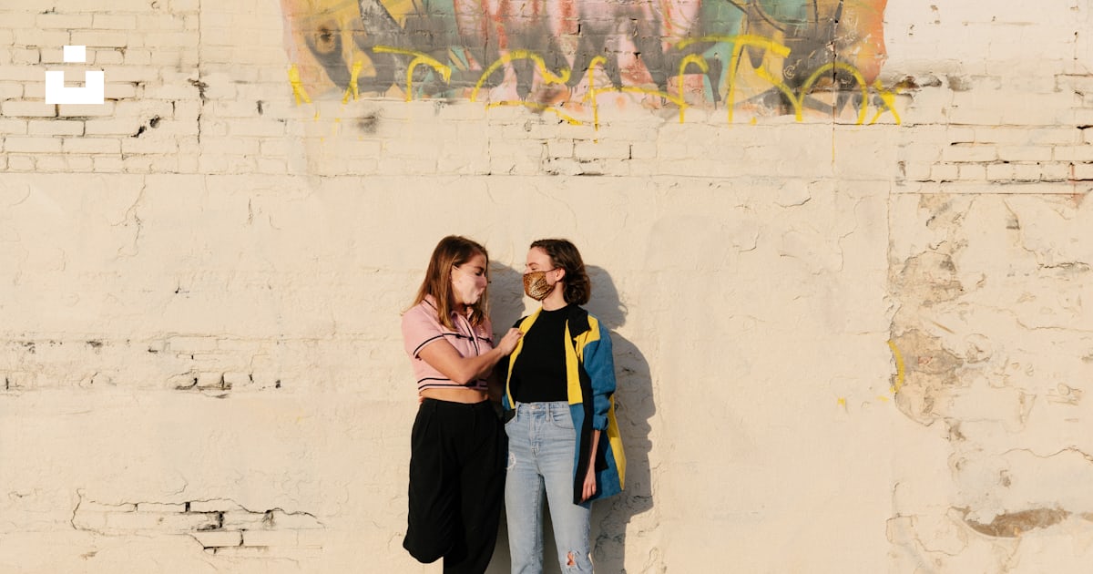 Woman In Black Tank Top And Blue Denim Jeans Standing Beside Woman In
