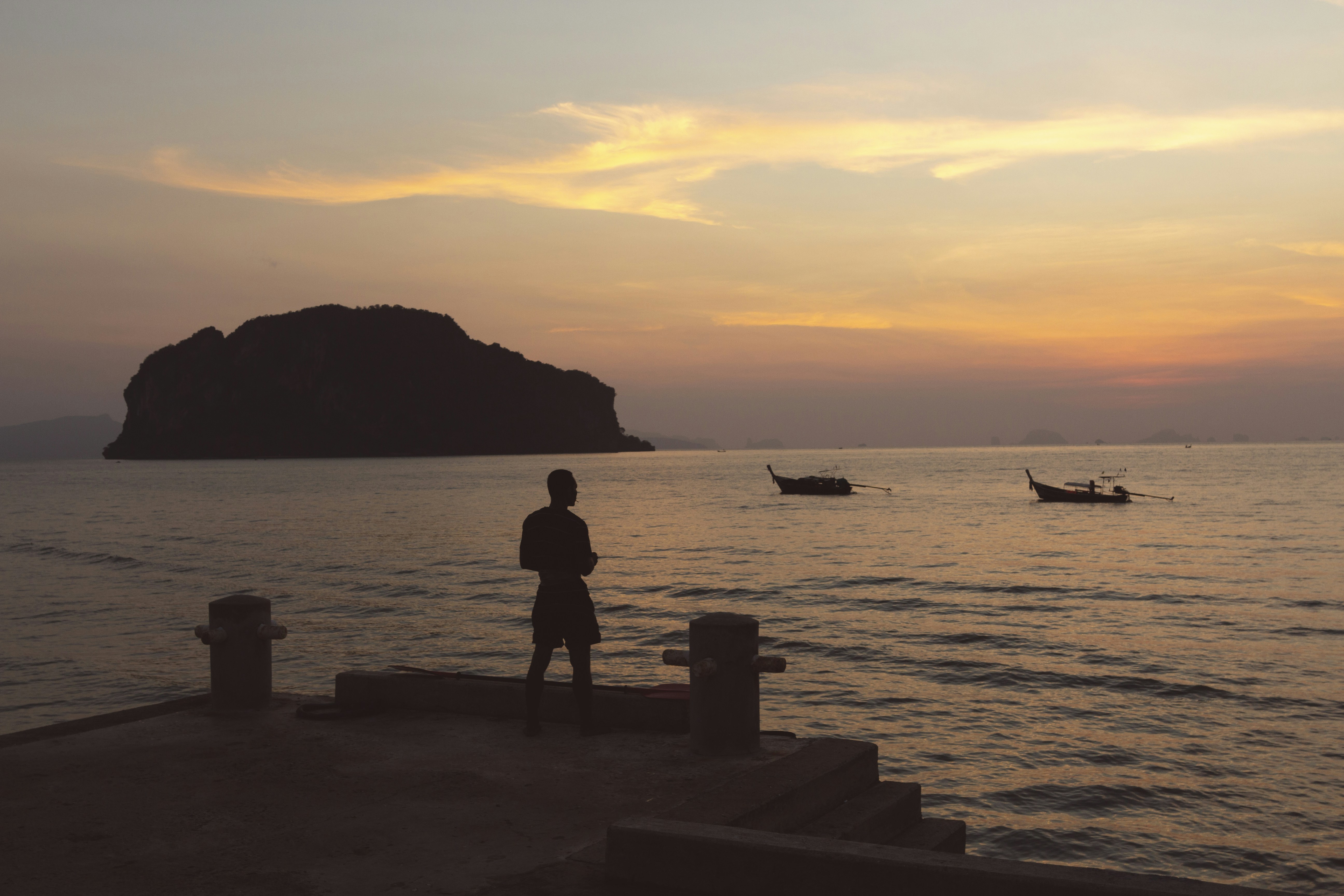 Silhouette at Dusk: A Lone Angler on the Pier Beneath a Golden Sunset