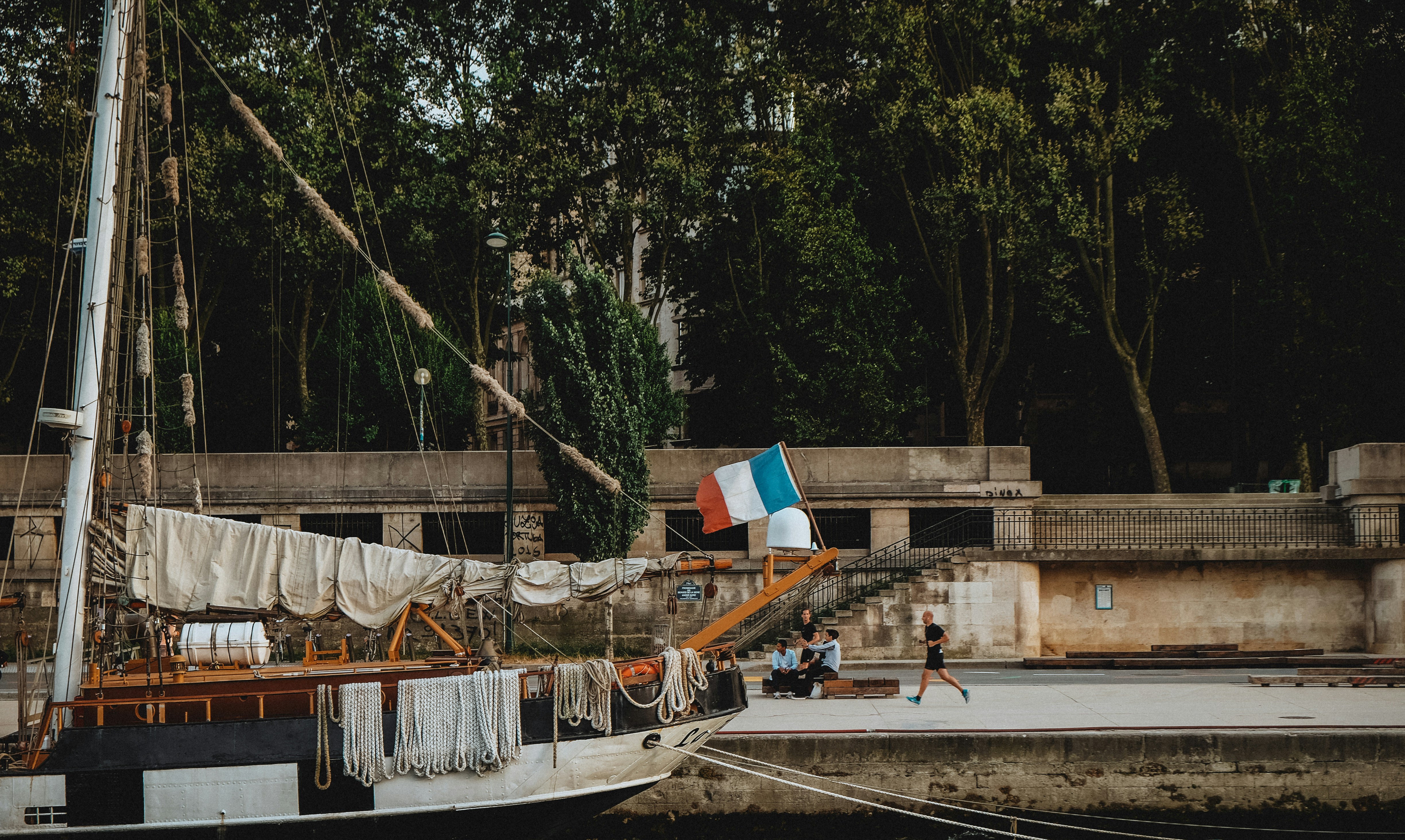 Quayside Sail: A French flag and boat at rest beside a stone quay