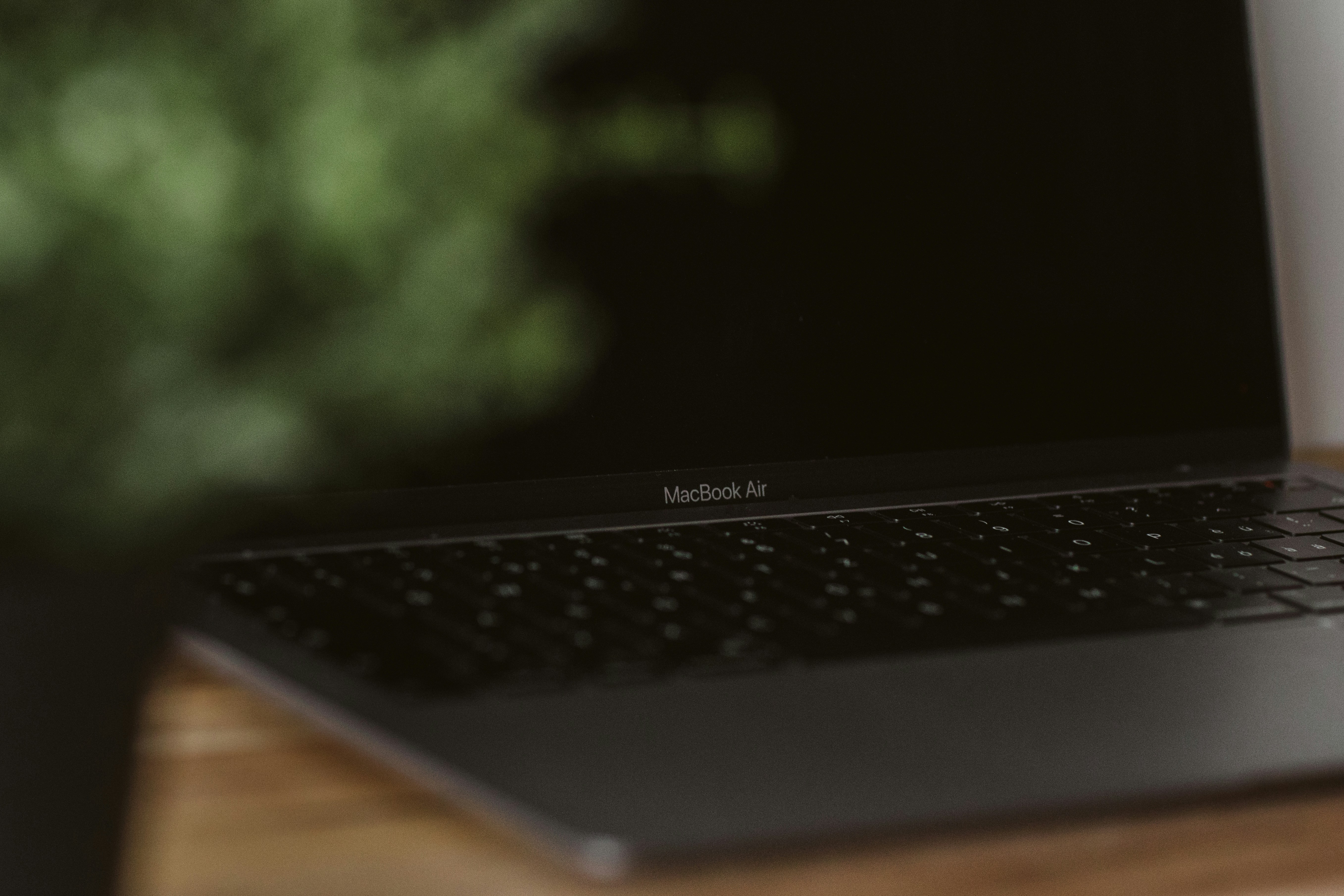 Midnight MacBook on a Wooden Desk: Subtle Reflections and Soft Focus