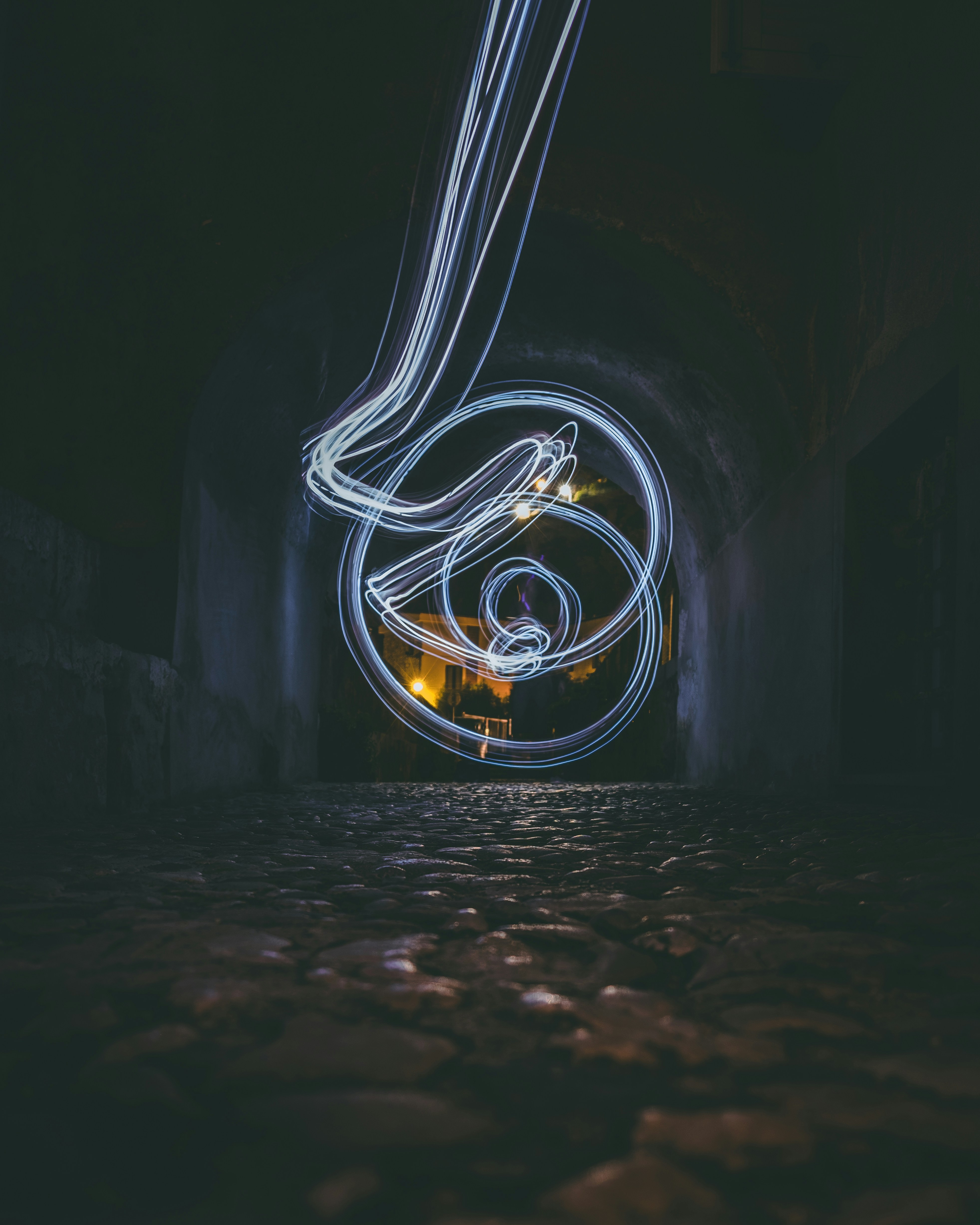 Spiral Light Glyphs Woven Through a Midnight Cobblestone Tunnel