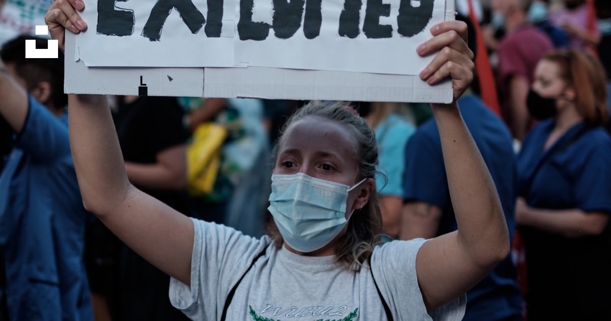 Mujer En Camiseta Blanca De Cuello Redondo Sosteniendo Un Tablero De