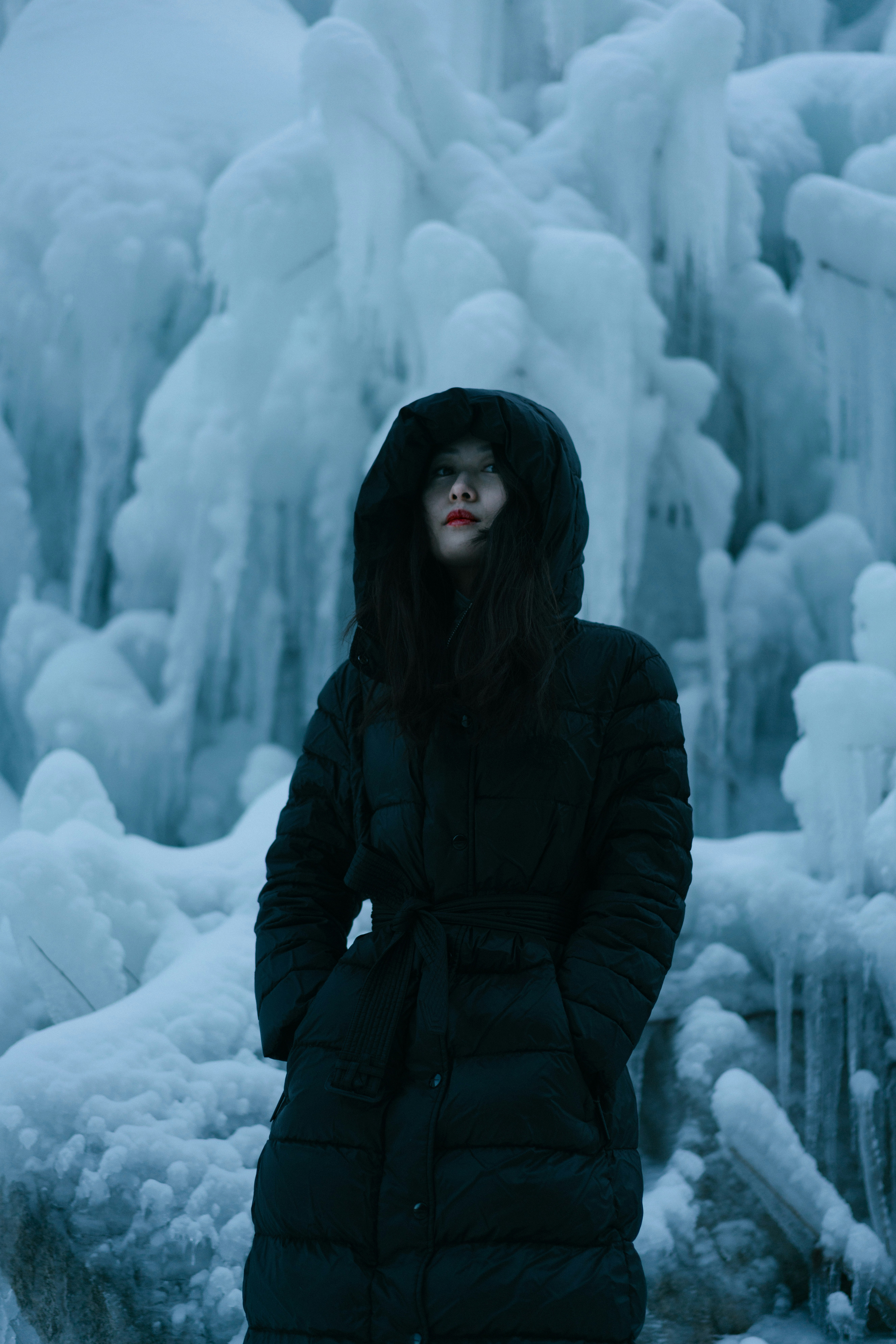 woman in black coat standing on snow covered ground
