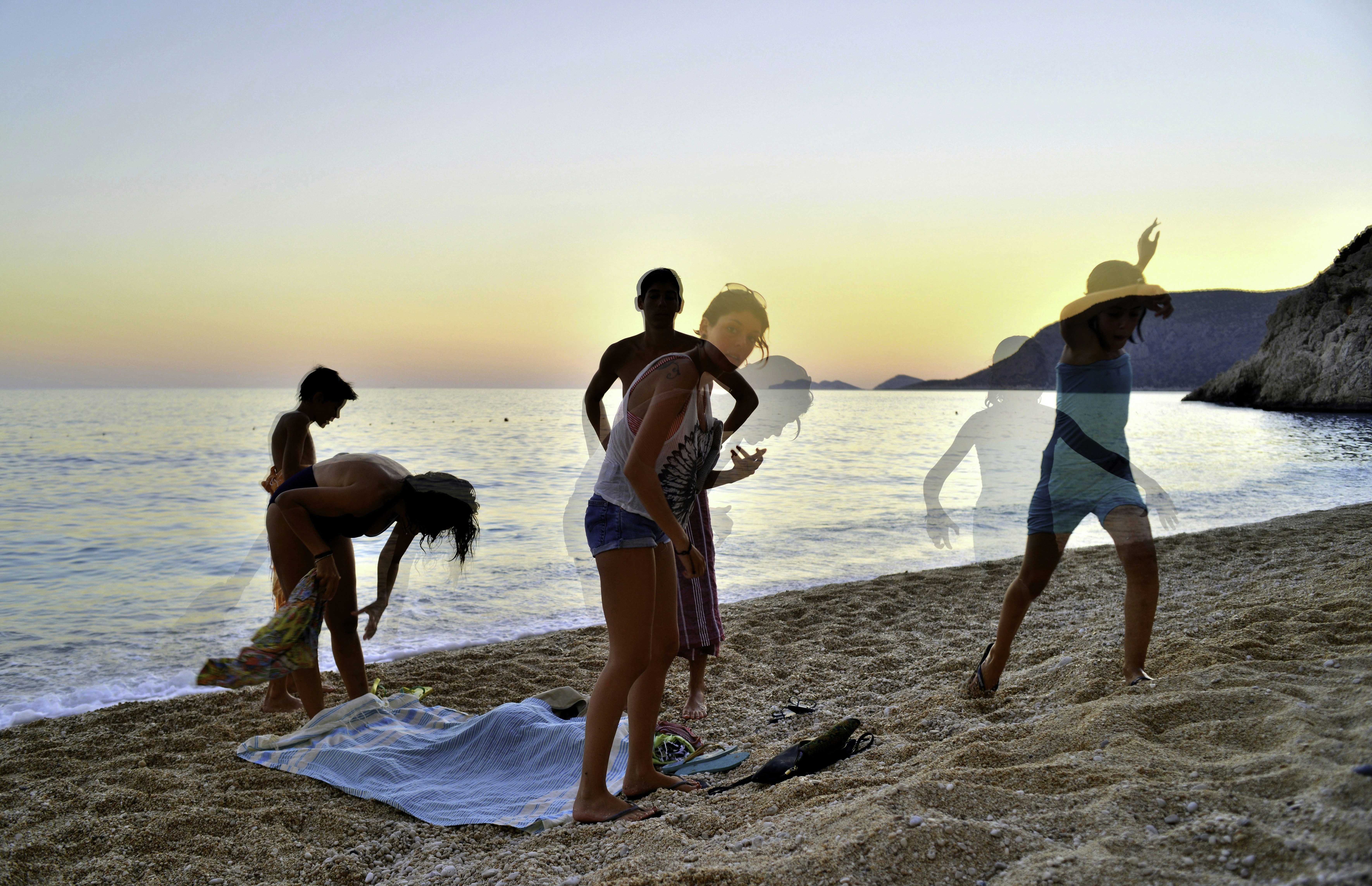 2 women in bikini walking on beach during sunset