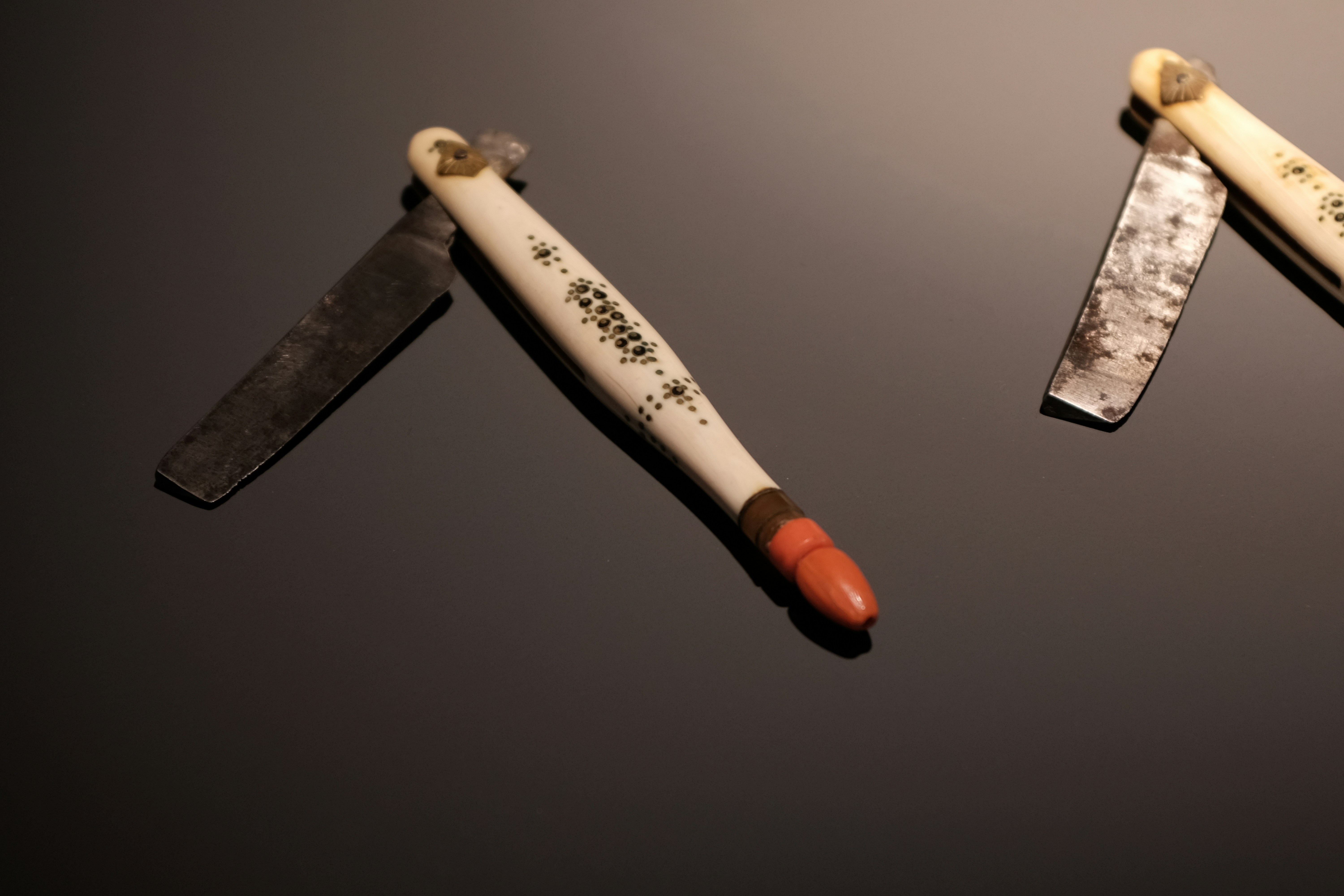 Orange-tipped anchor among a diagonal trio of vintage blades