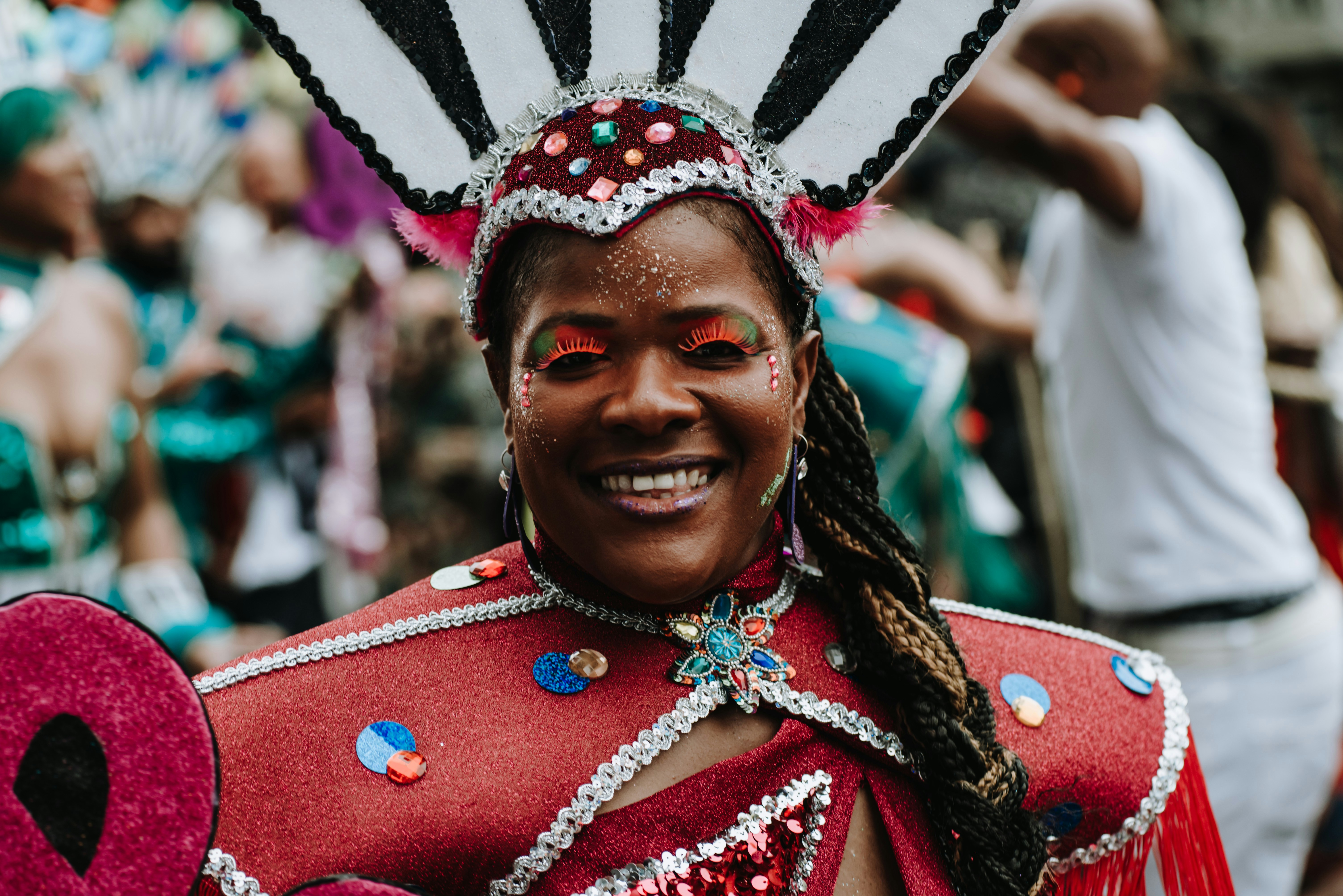 Smiling participant in a colorful, bejeweled costume at a lively parade.