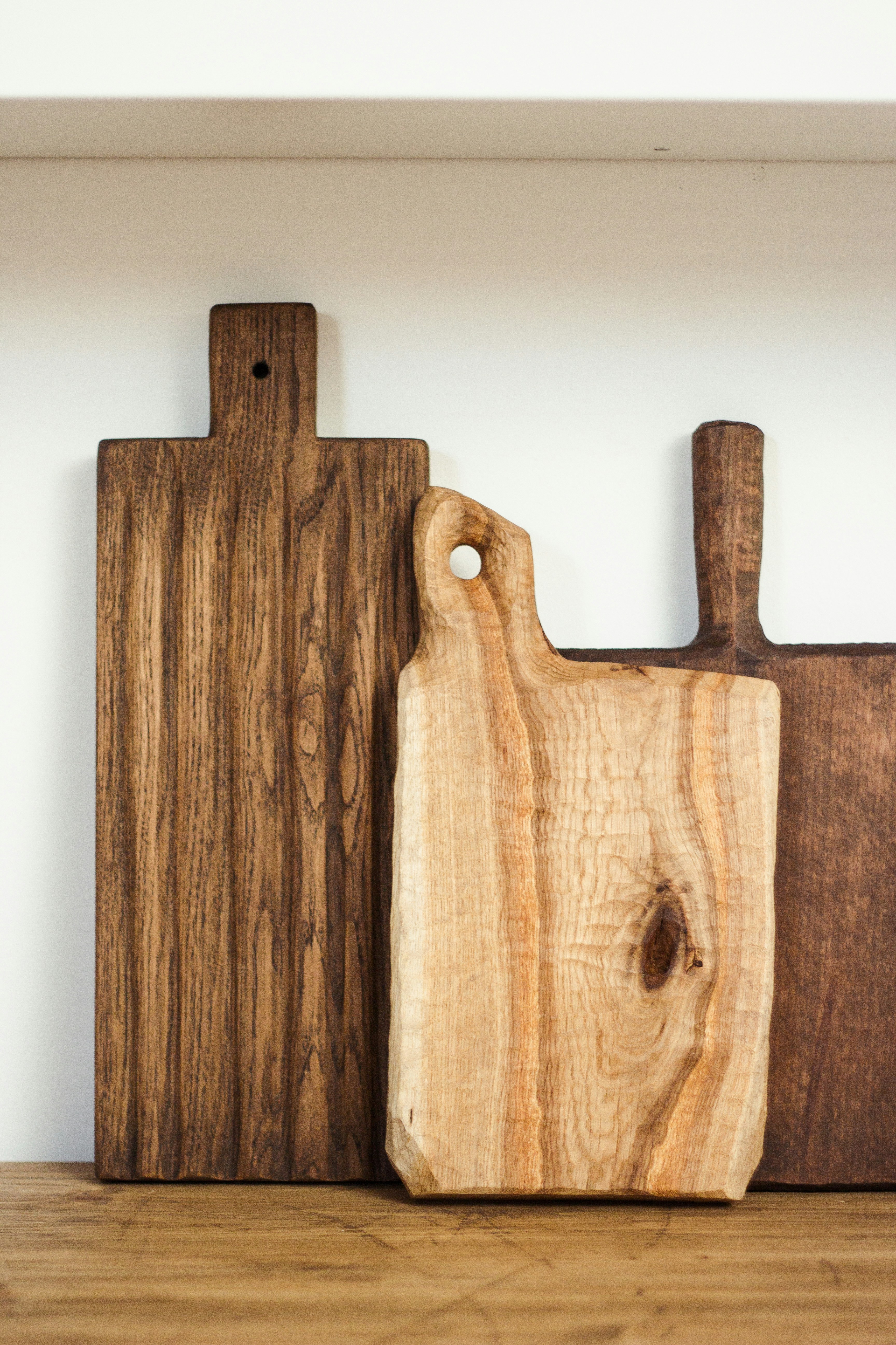 Three distinct wooden cutting boards with varying textures and colors arranged artistically against a neutral backdrop.