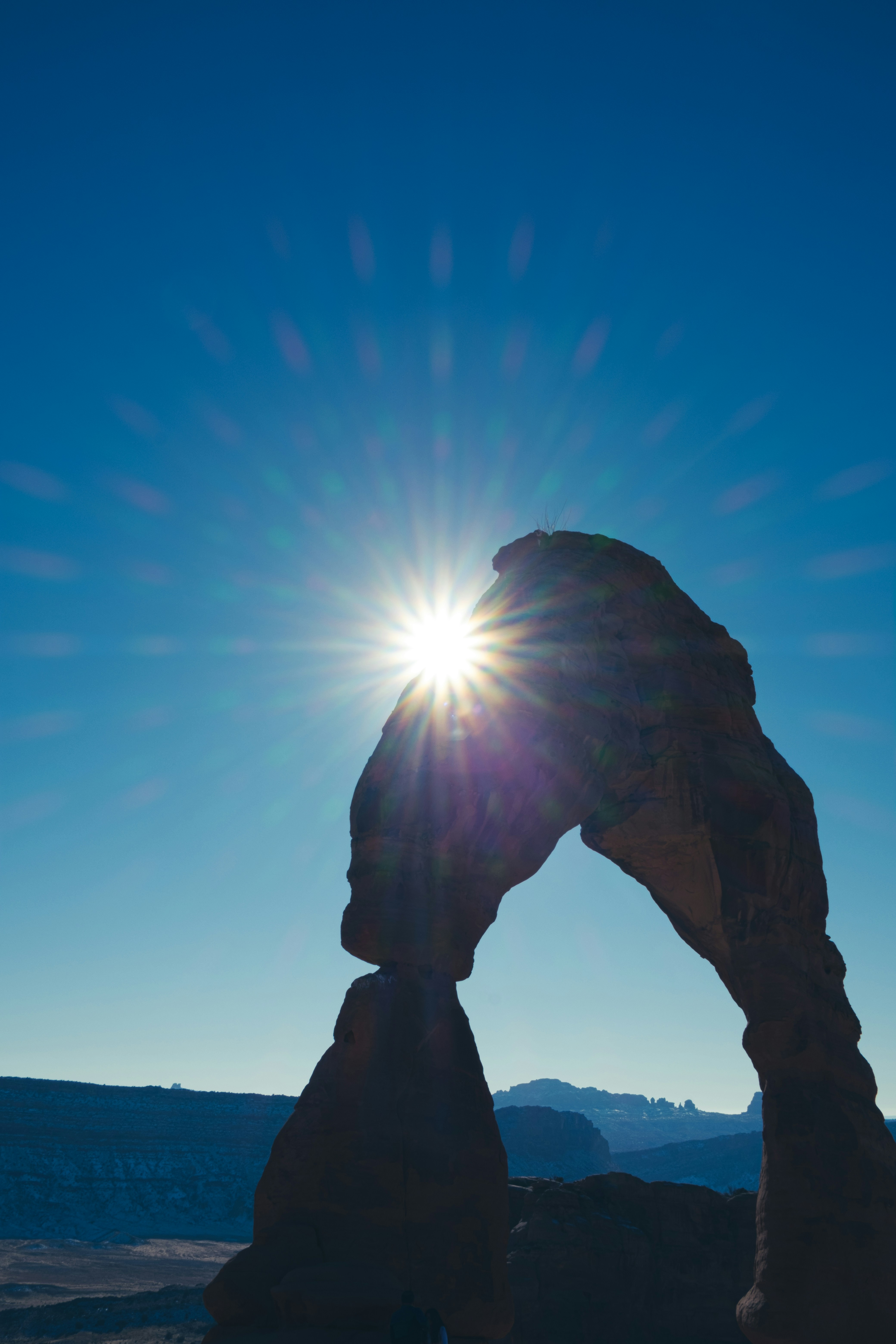 Sunburst Through Delicate Arch Against a Pristine Blue Desert Sky
