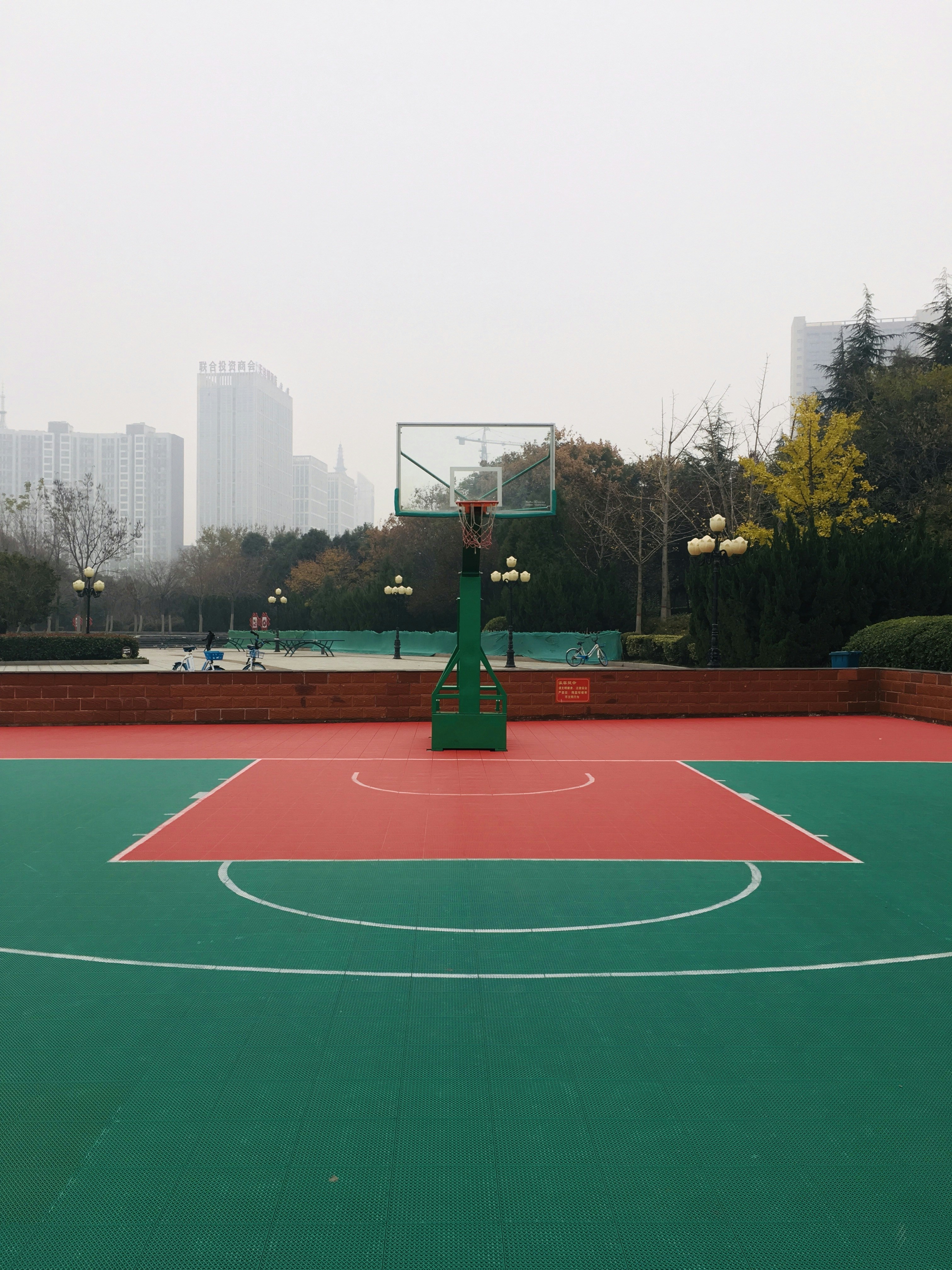 Hoop in the Haze: A Quiet City Park Court Framed by a Distant Skyline