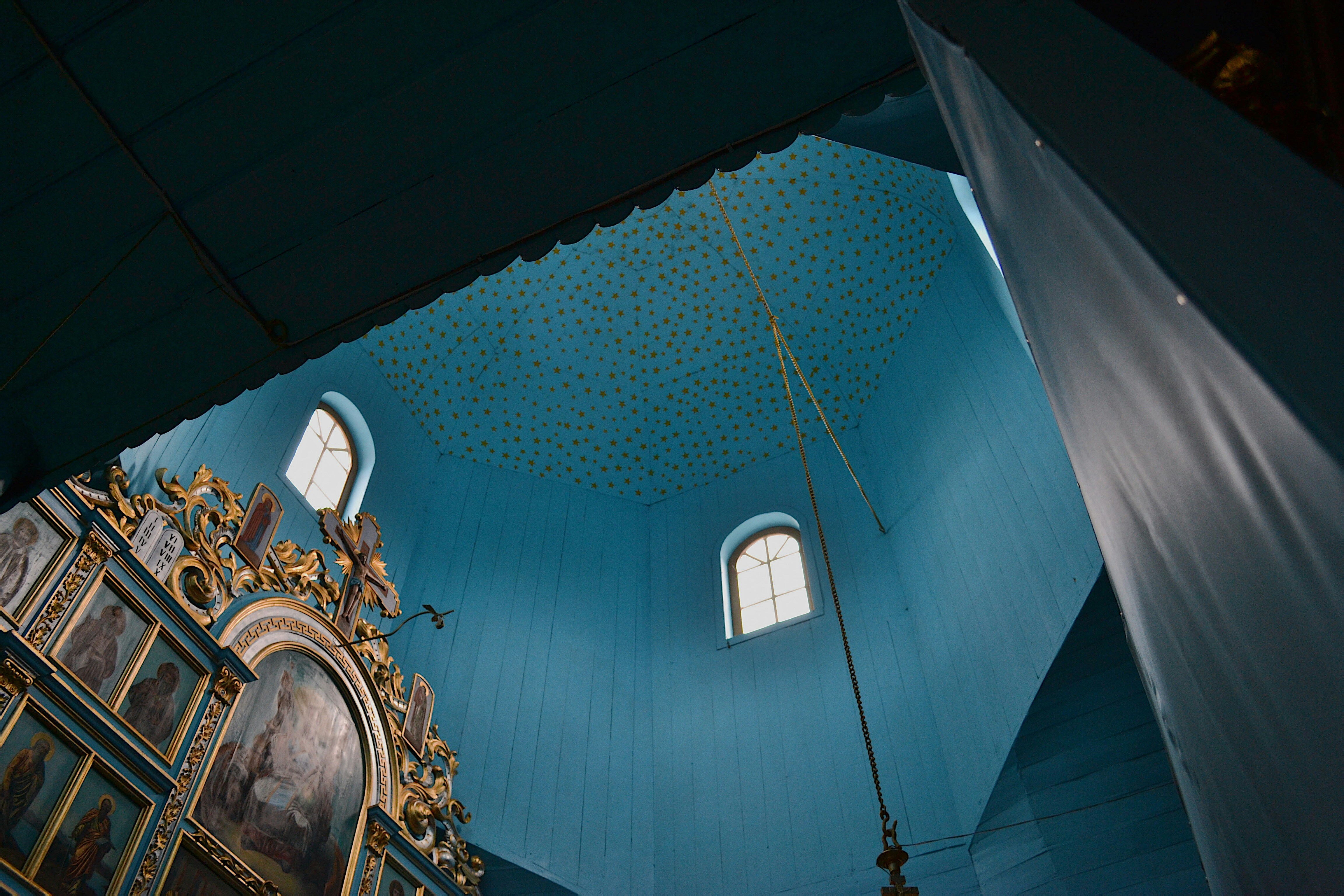 Interior view of a church showcasing a striking blue ceiling adorned with stars, contrasted by ornate decorations below.