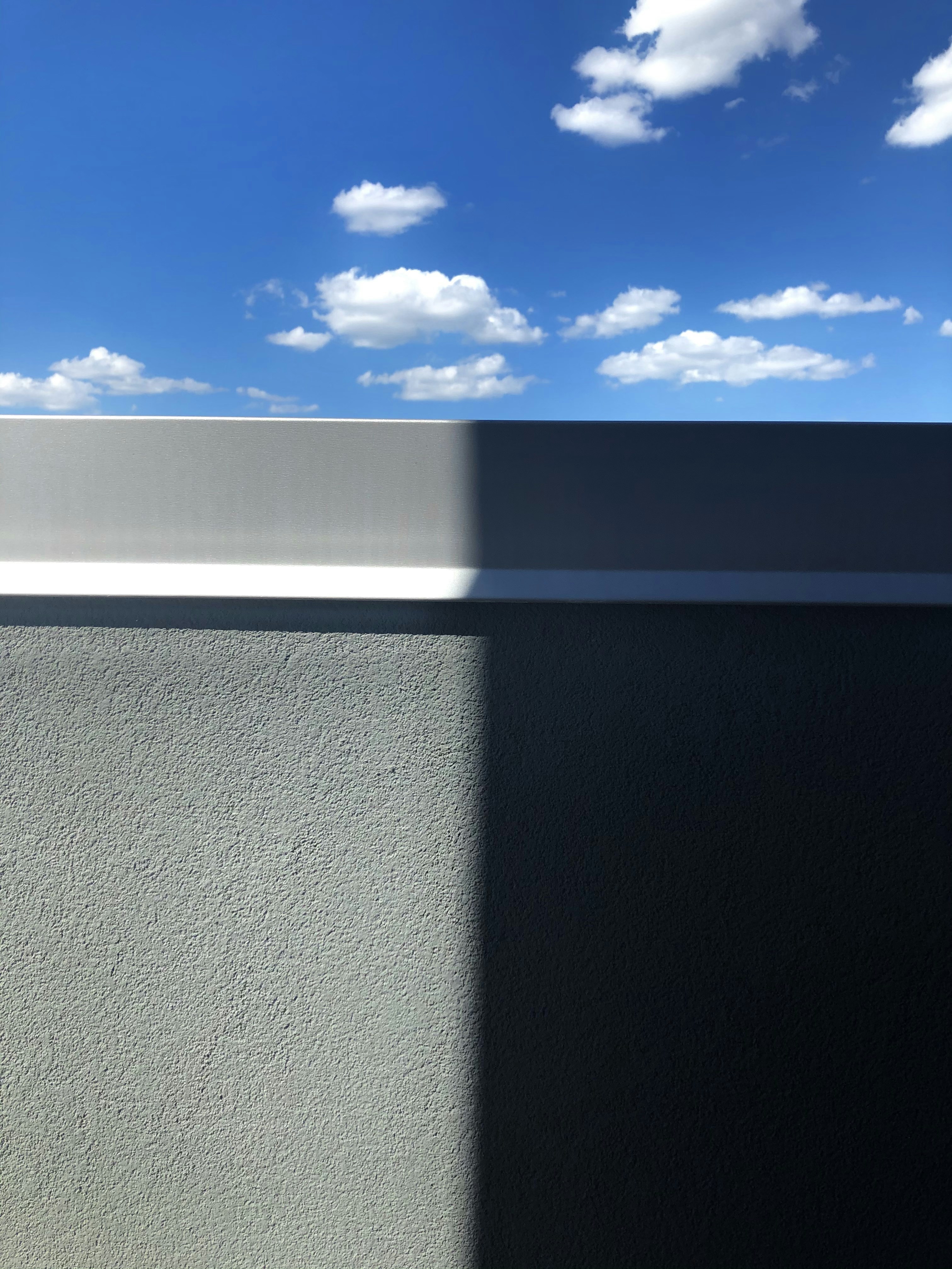 Vertical Shadow Boundary on a Textured Parapet Under a Bright Blue Sky