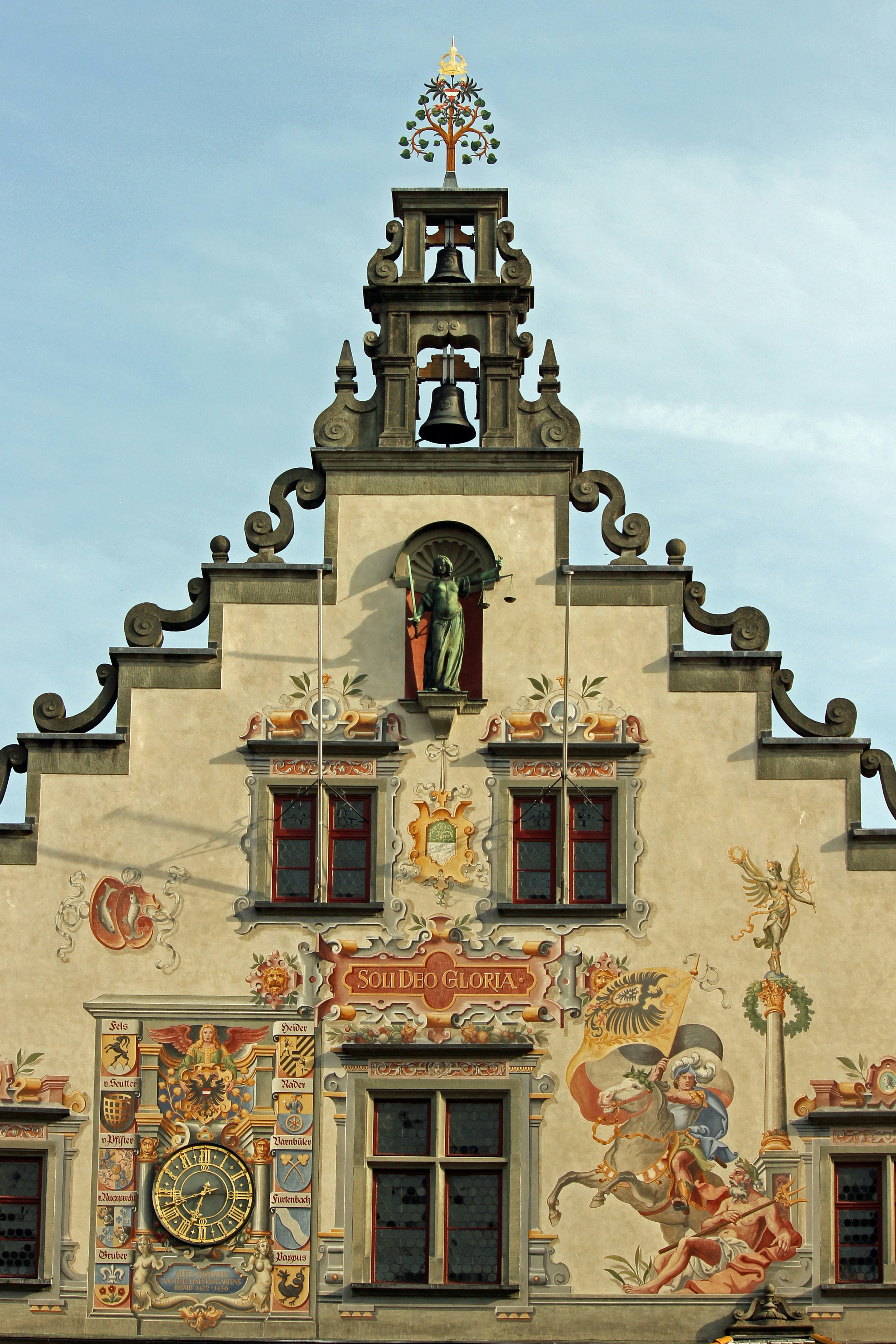 Intricately decorated facade of a historical building featuring vibrant murals, a clock, and a statue, showcasing architectural artistry.