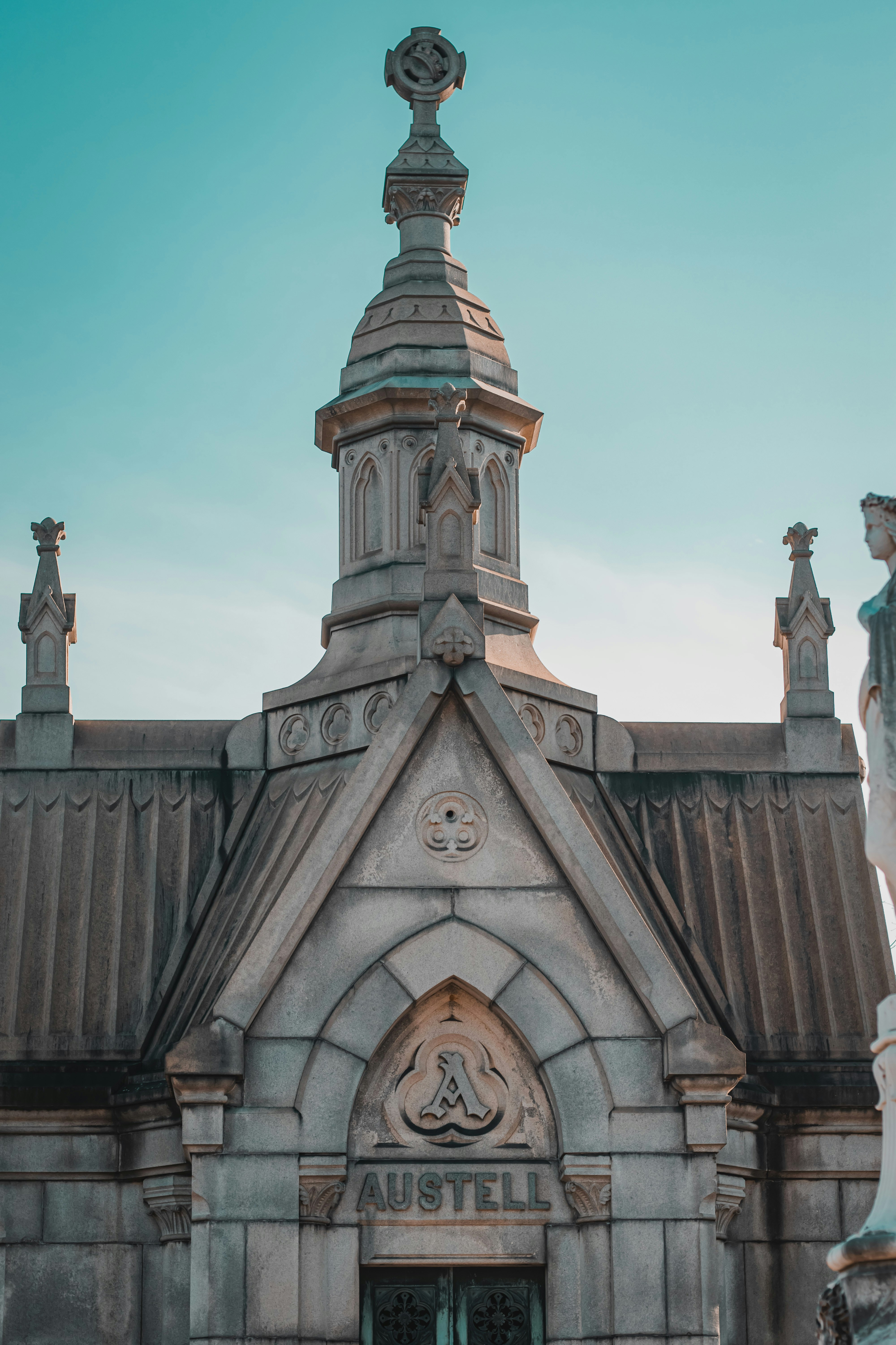 Intricately designed mausoleum featuring a prominent steeple and detailed stonework, set against a clear blue sky.