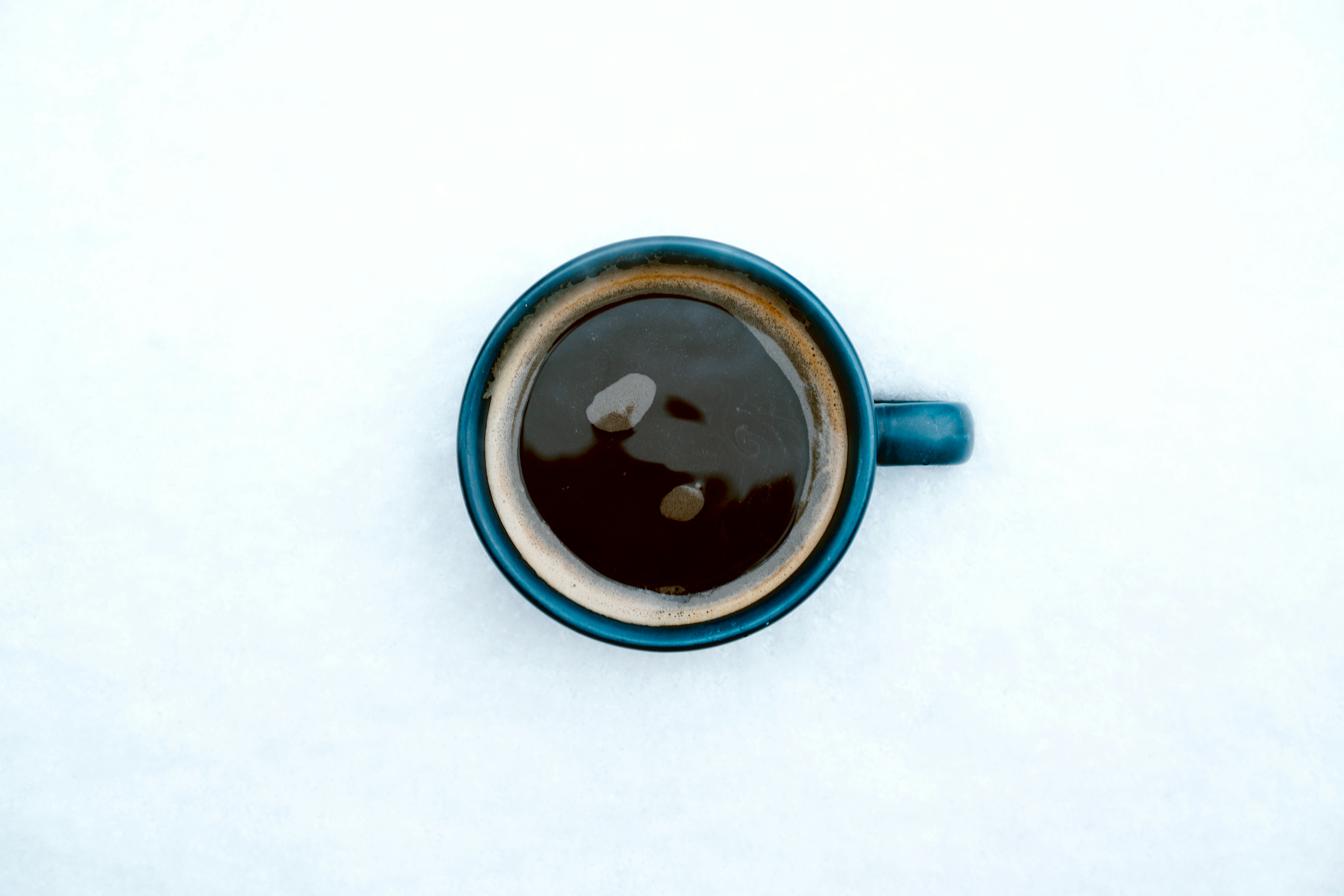 Blue ceramic mug filled with coffee, centered on a white background.