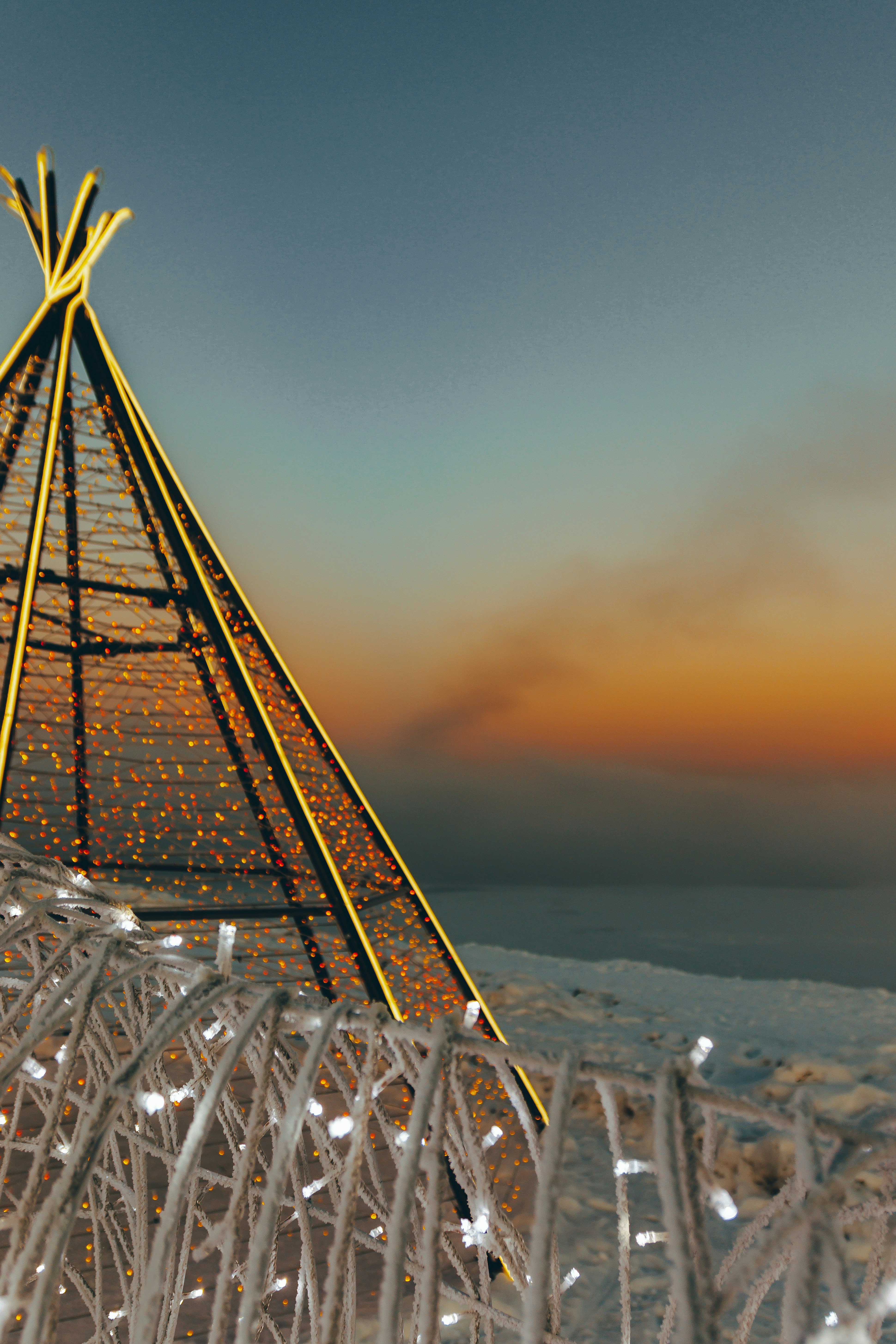 Glowing triangular beacon above a sea of clouds at sunset